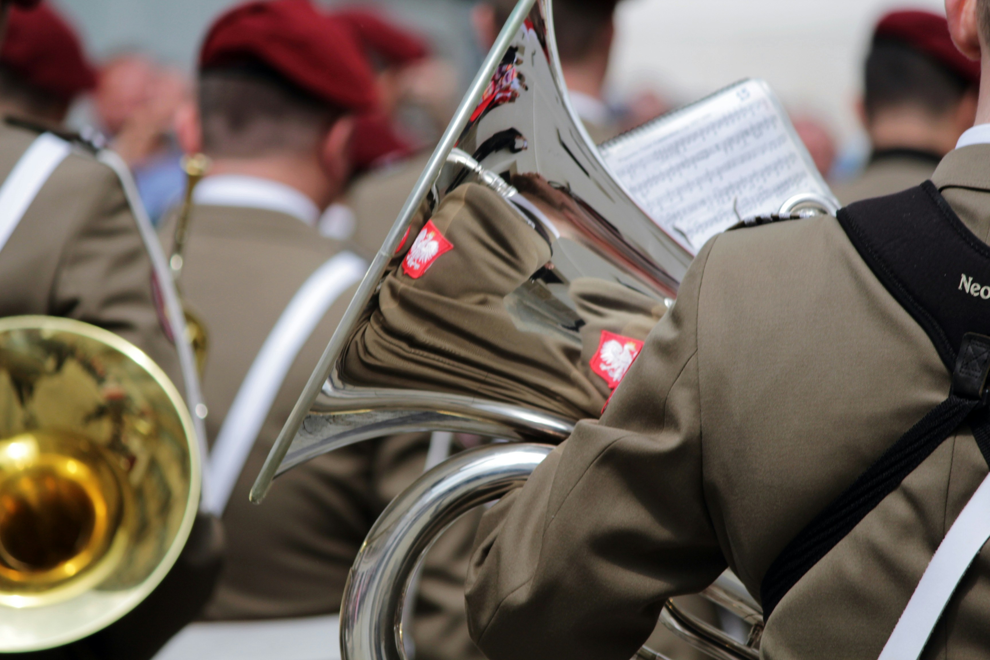 Musicians in red berets play brass instruments during an outdoor event.