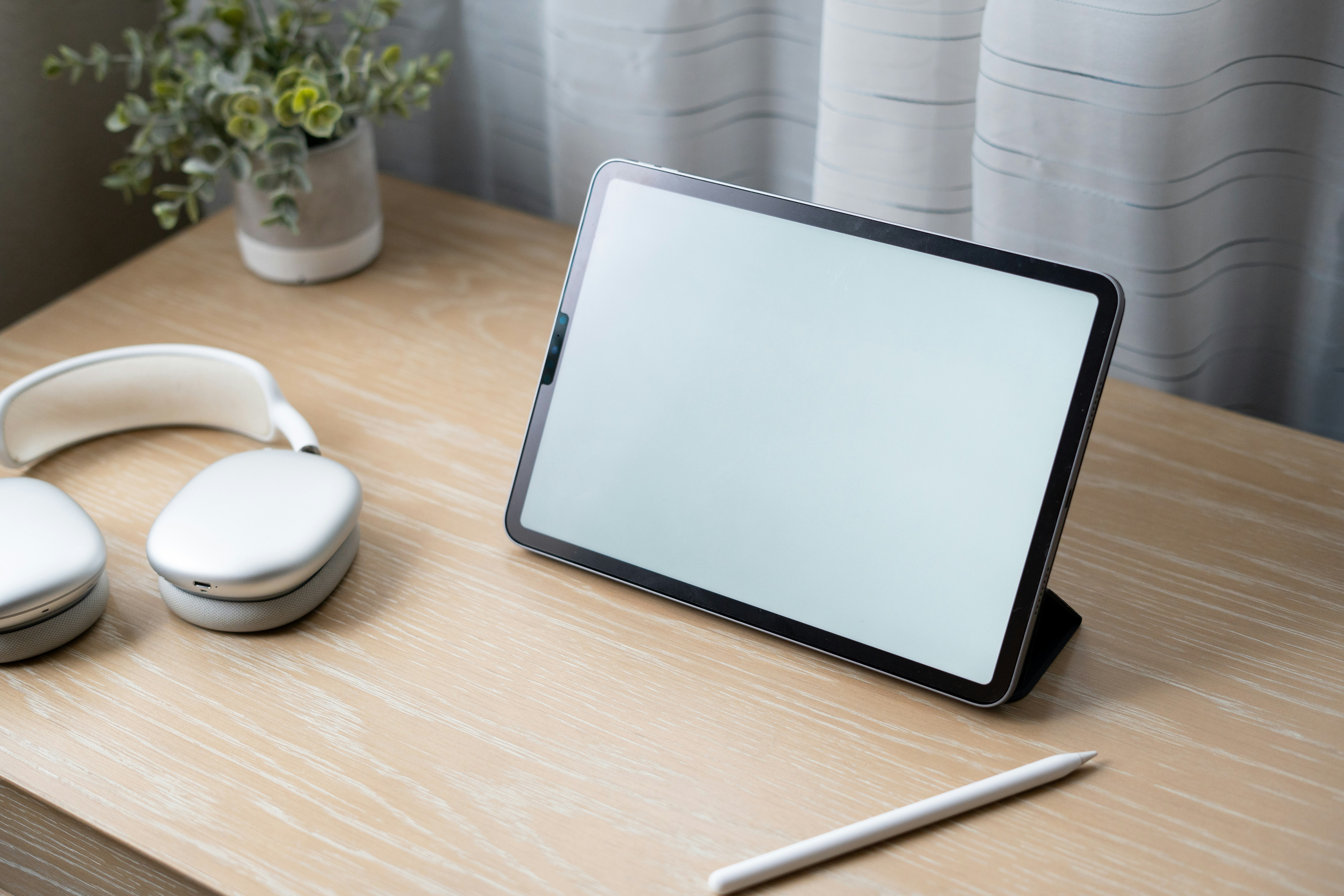 A tablet and headphones on a table photo – Free Desk setup Image on ...