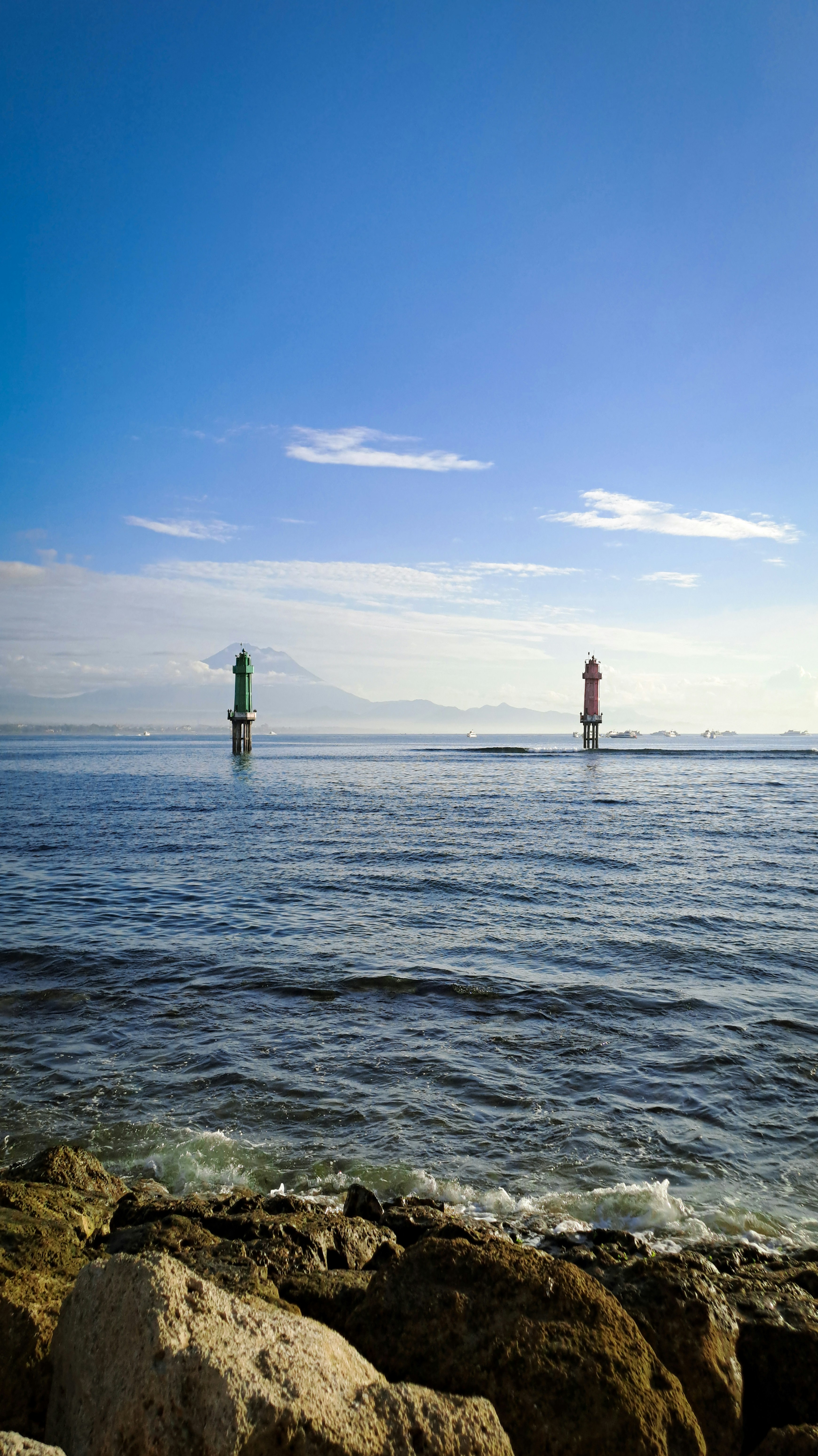 Twin Lighthouses off the Coast of Sanur, Denpasar, Bali | a large body of water with a lighthouse in the distance