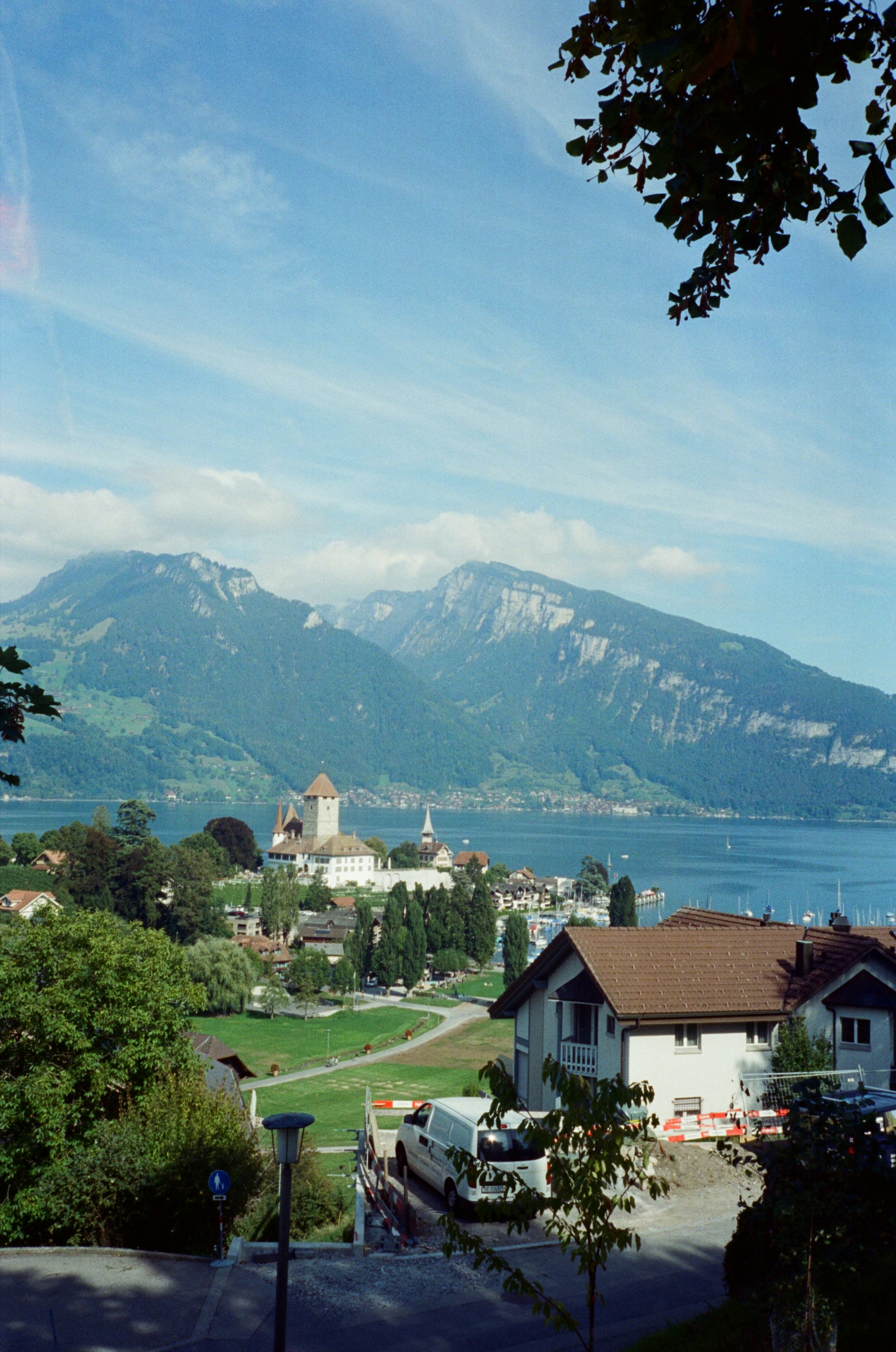 Lakeside village beneath towering Alps, with tranquil waters and inviting hillside road