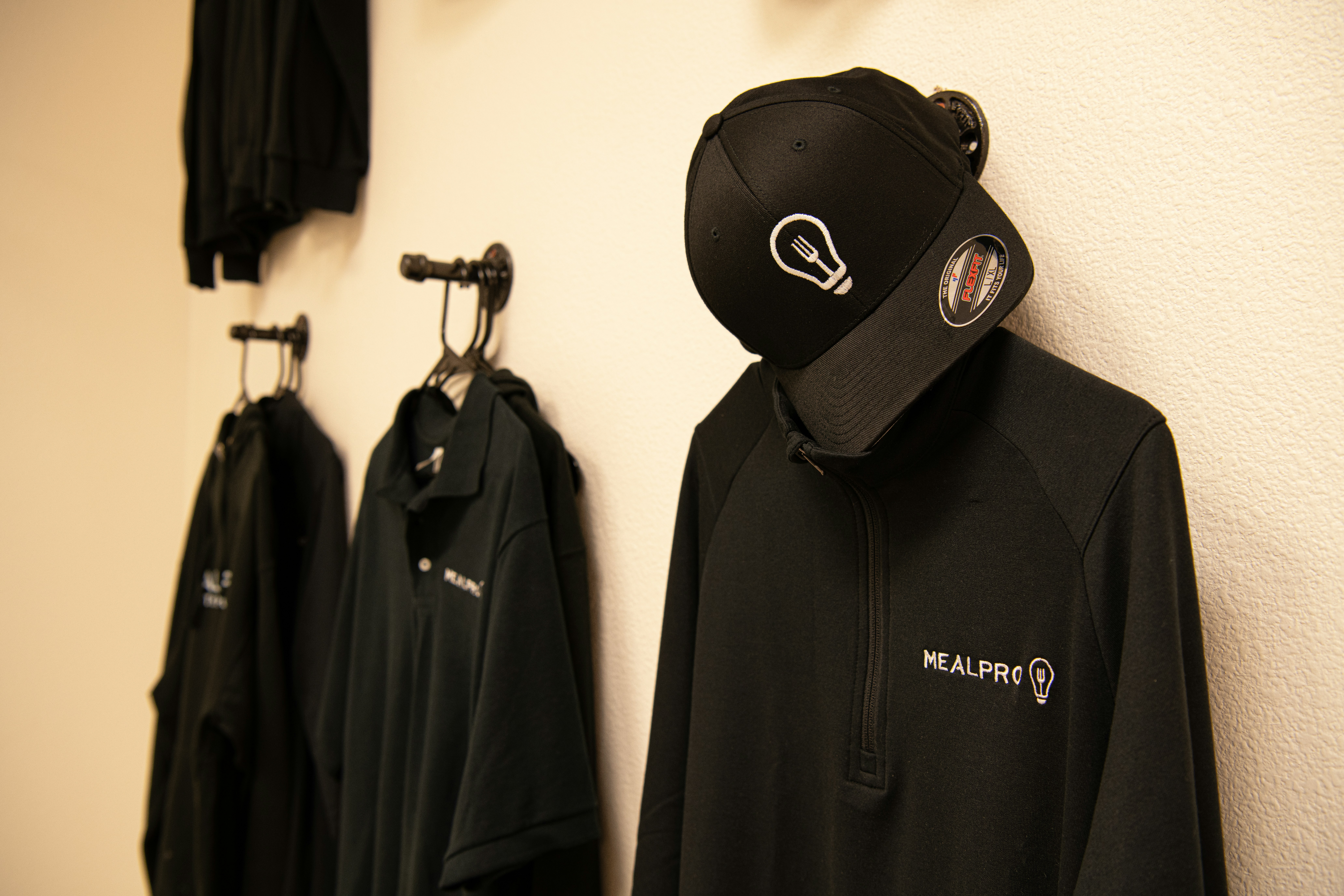 Muted Apparel Gallery: A Black Polo and Cap Rest Against a Cream Wall