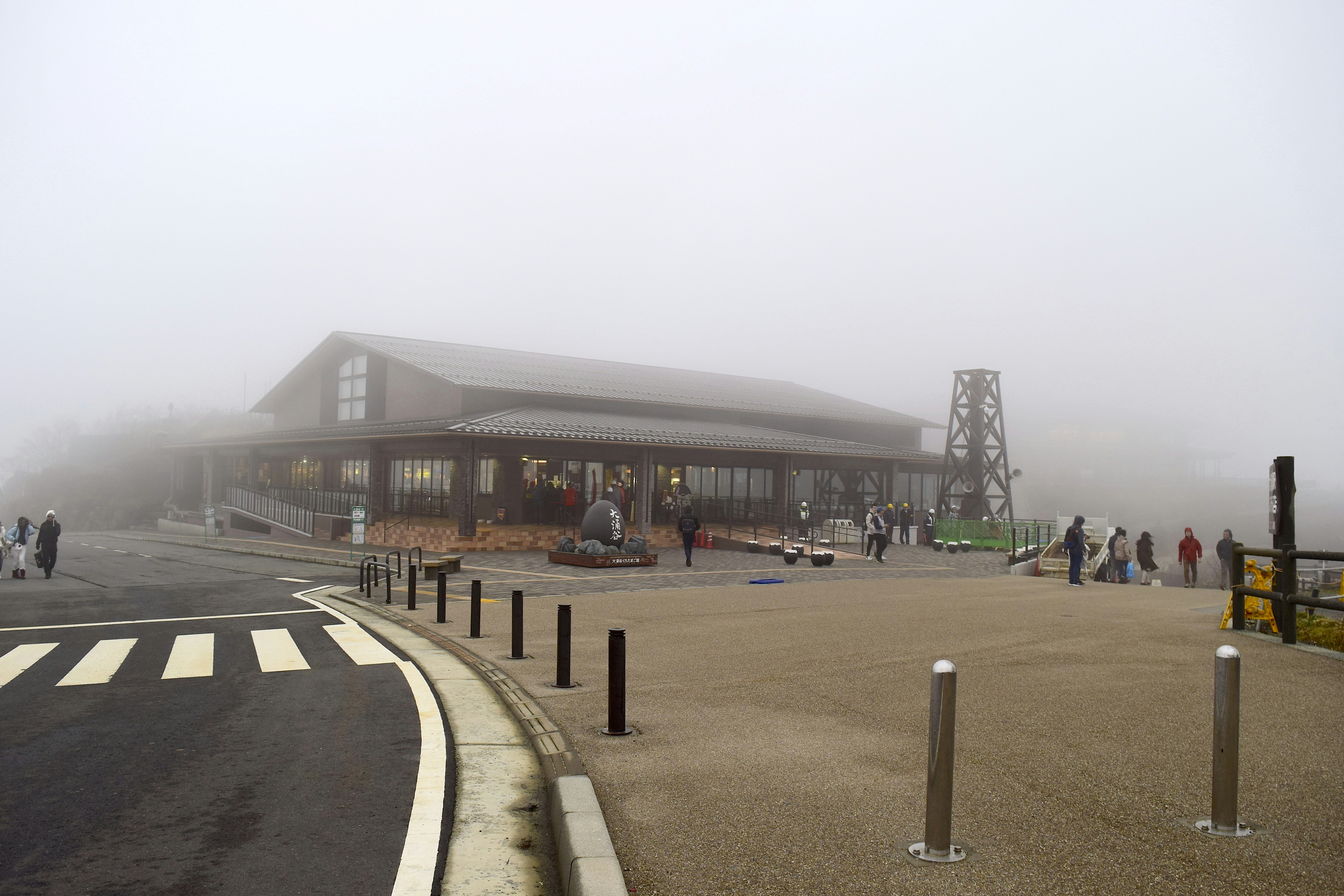 Mist-Clad Visitor Center Emerges From the Fog Along a Curving Promenade