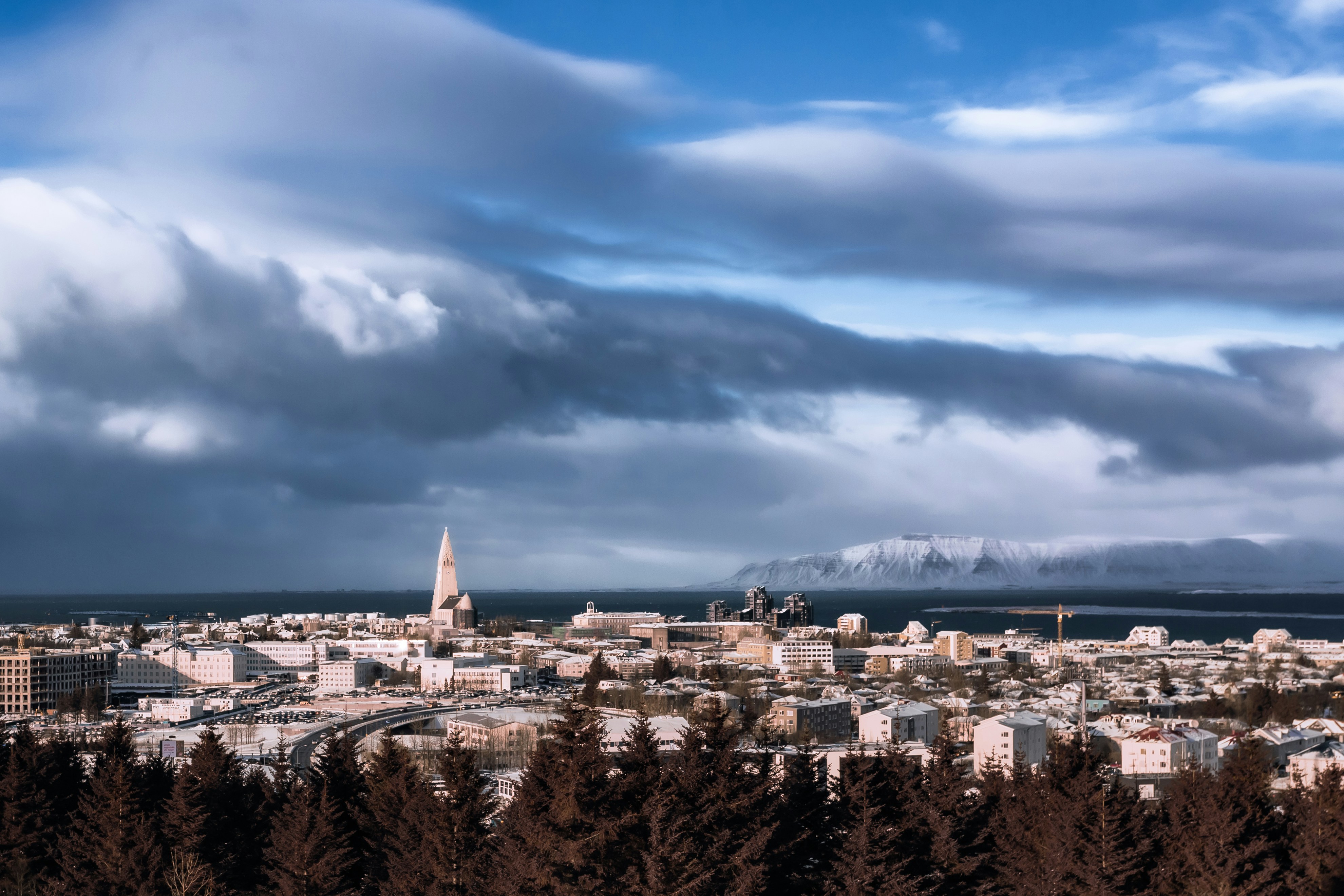 Elevated cityscape beneath dramatic clouds and distant mountains