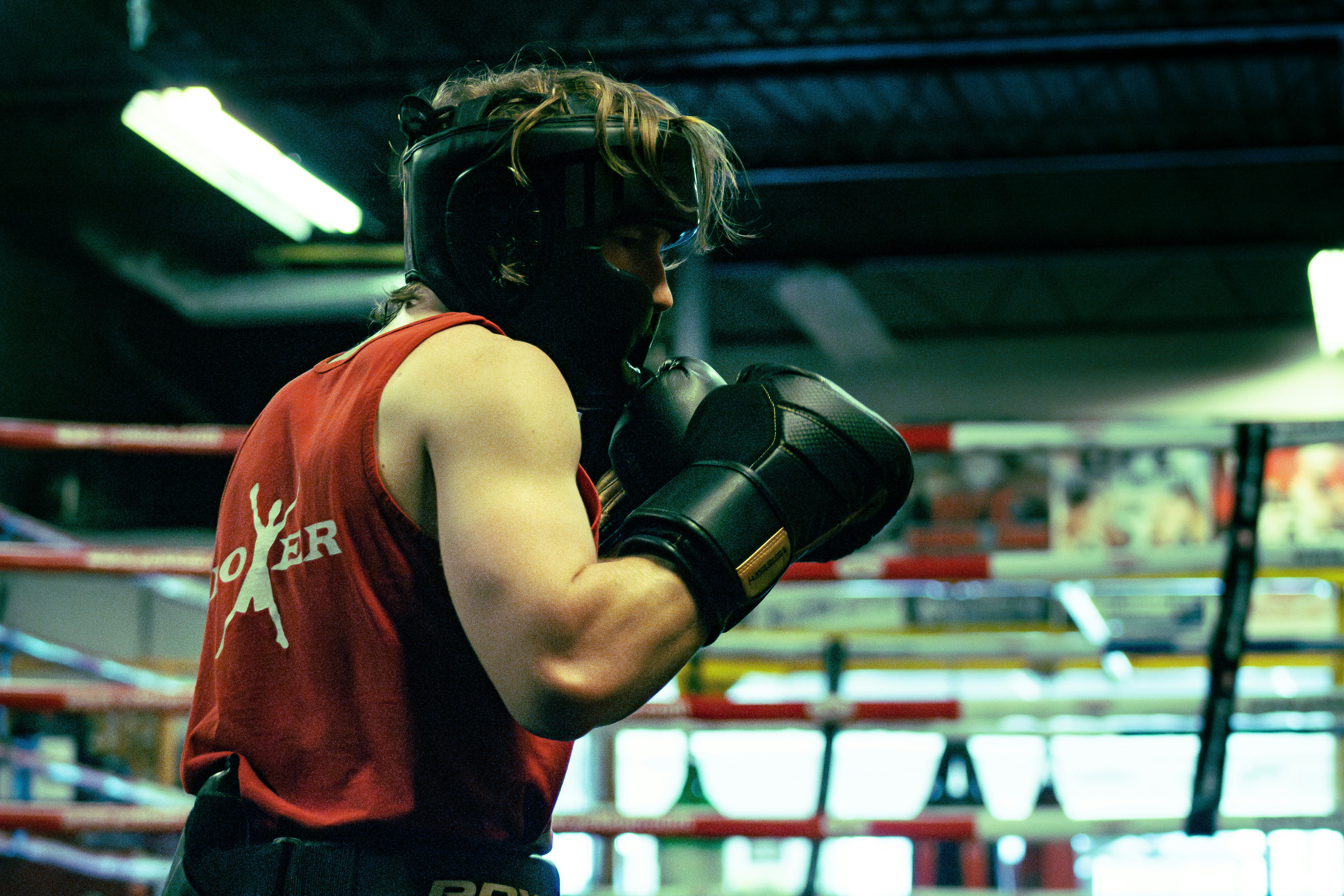 A man in a boxing ring wearing a red shirt and black boxing gloves ...