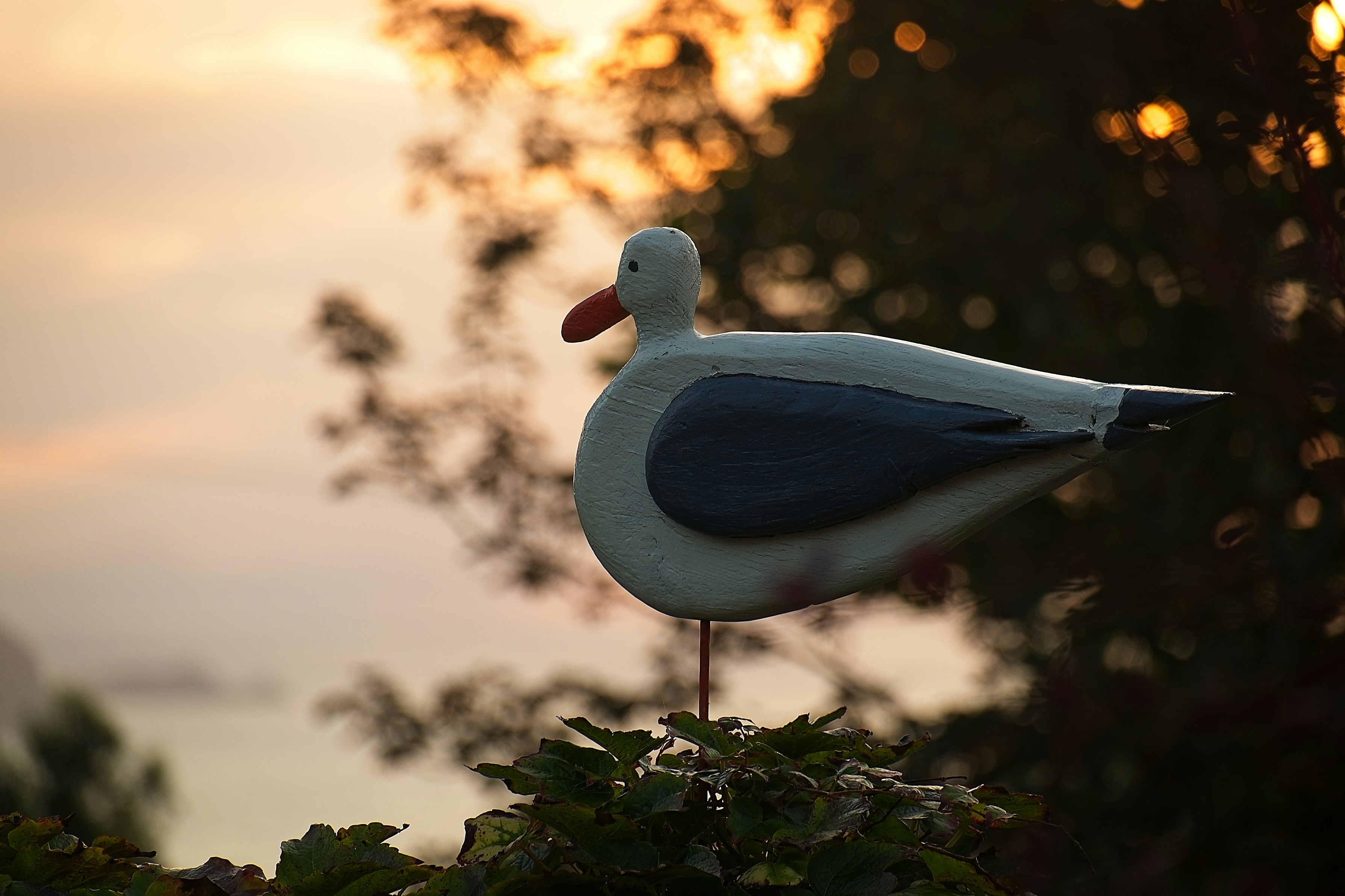 Dusk Sentinel: A Seagull Statue Perched Over Quiet Water