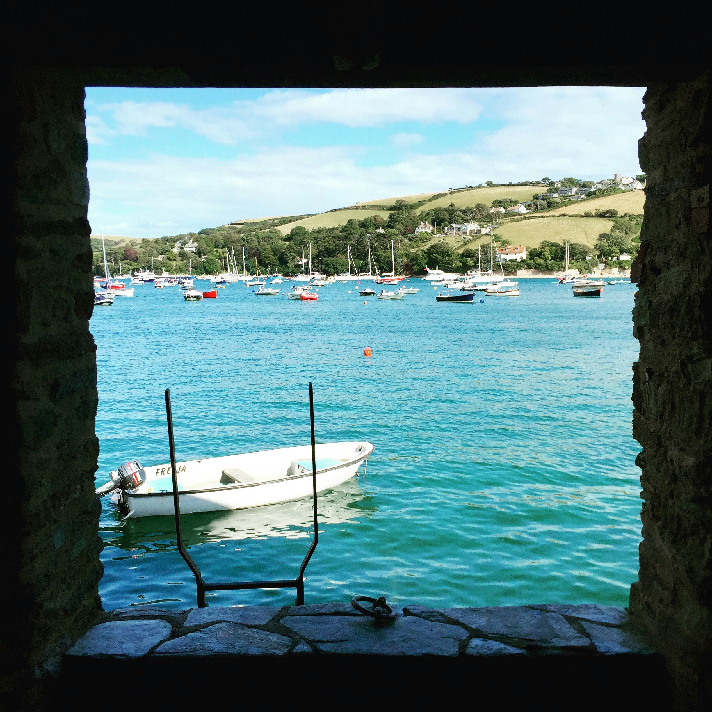 Harbor beyond the stone frame: boats anchored along blue water
