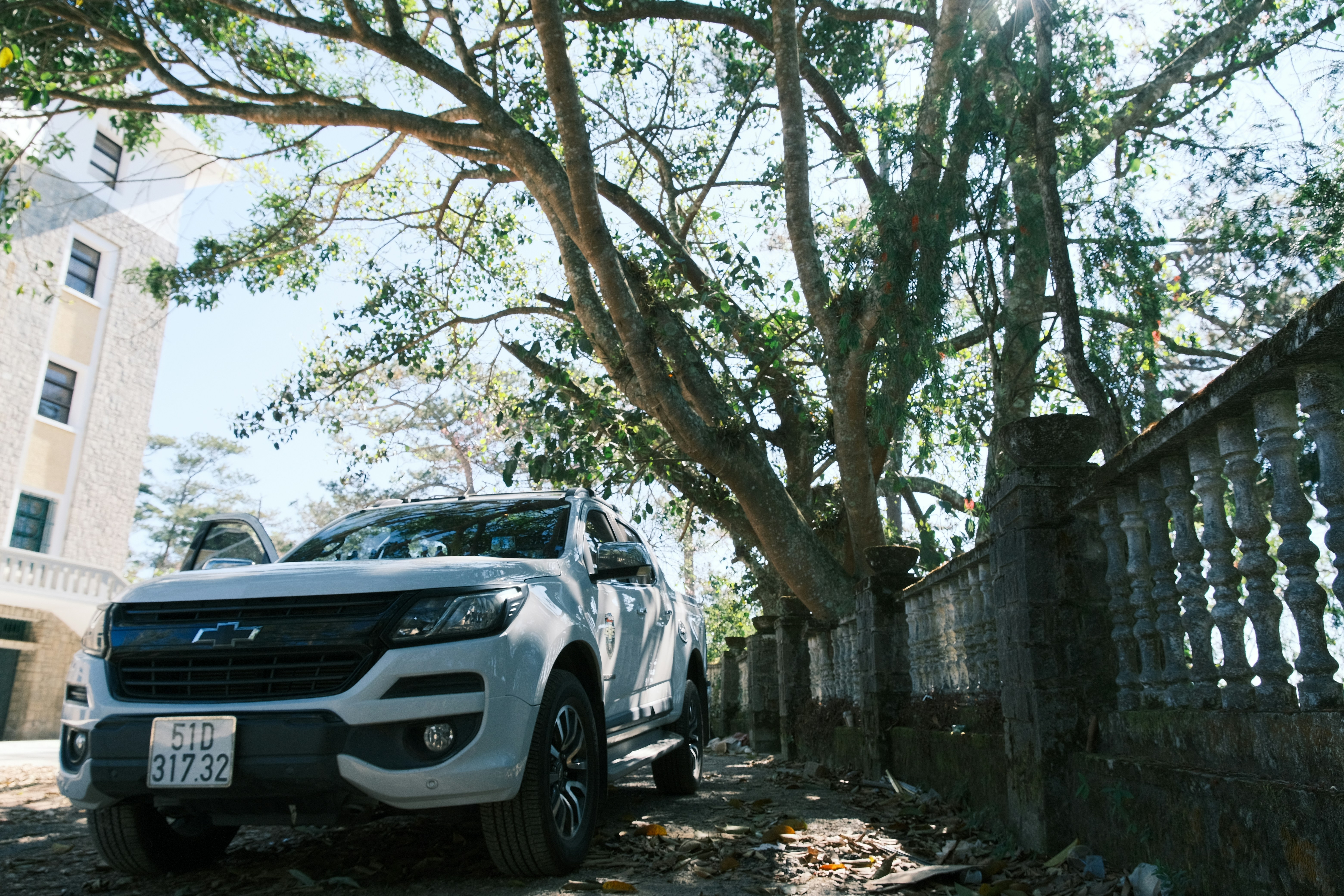 Chevrolet pickup under a sunlit canopy near an old stone railing