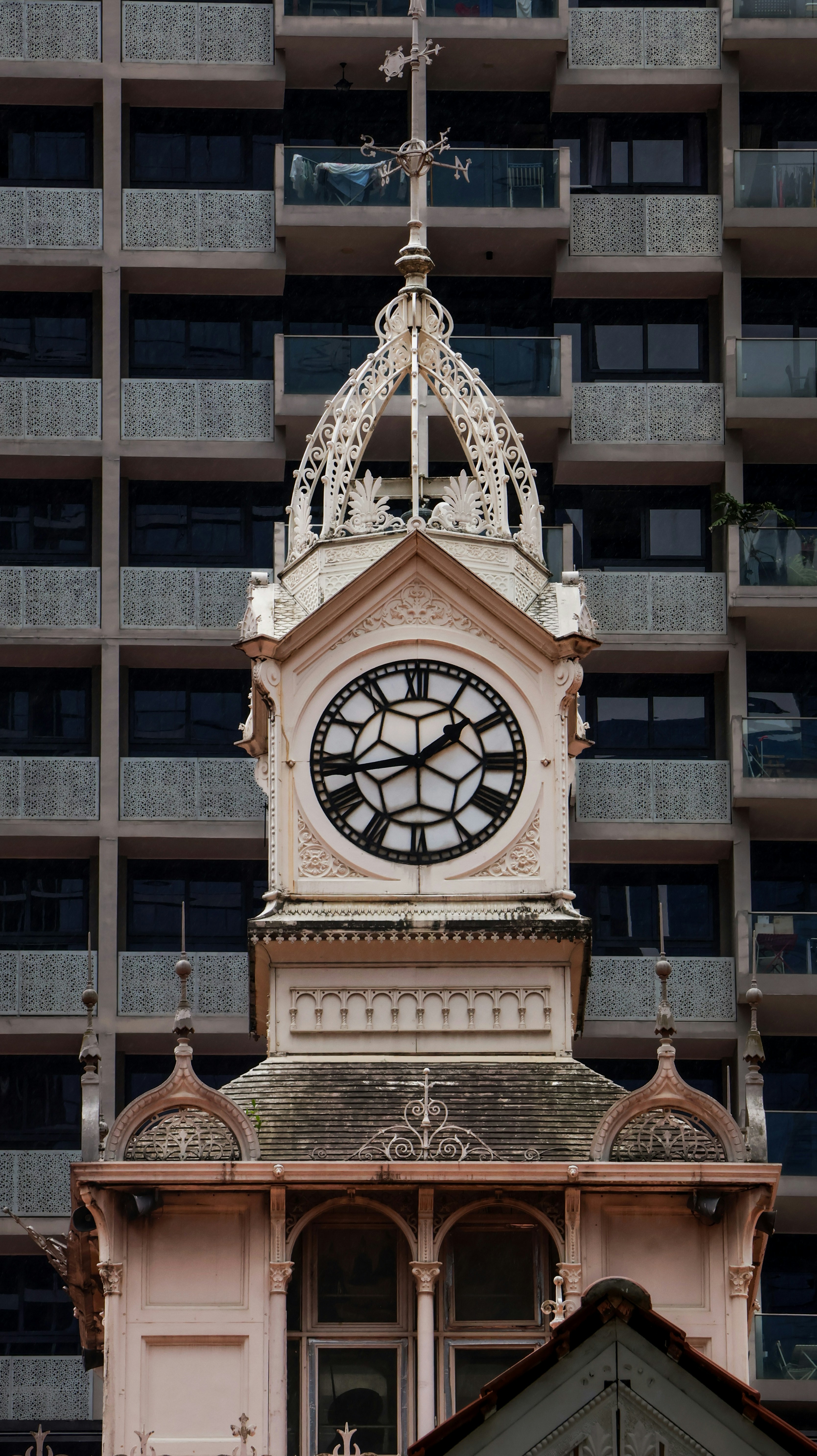 Timekeeper Between Glass: A Victorian Clock Tower Amid a Modern City Grid