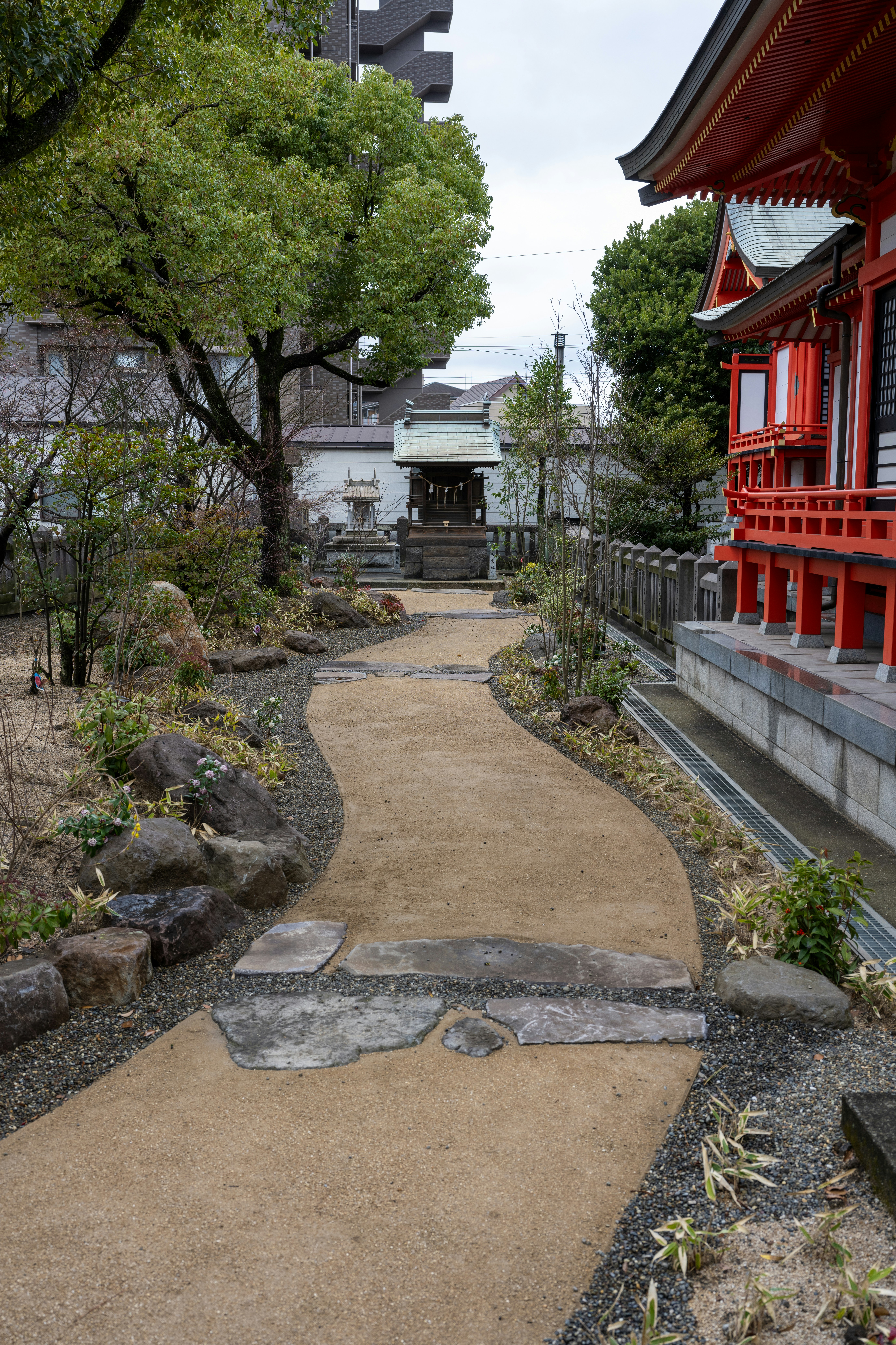 Crimson Pavilion Framing a Quiet Shrine Along a Stone-and-Sand Garden Path