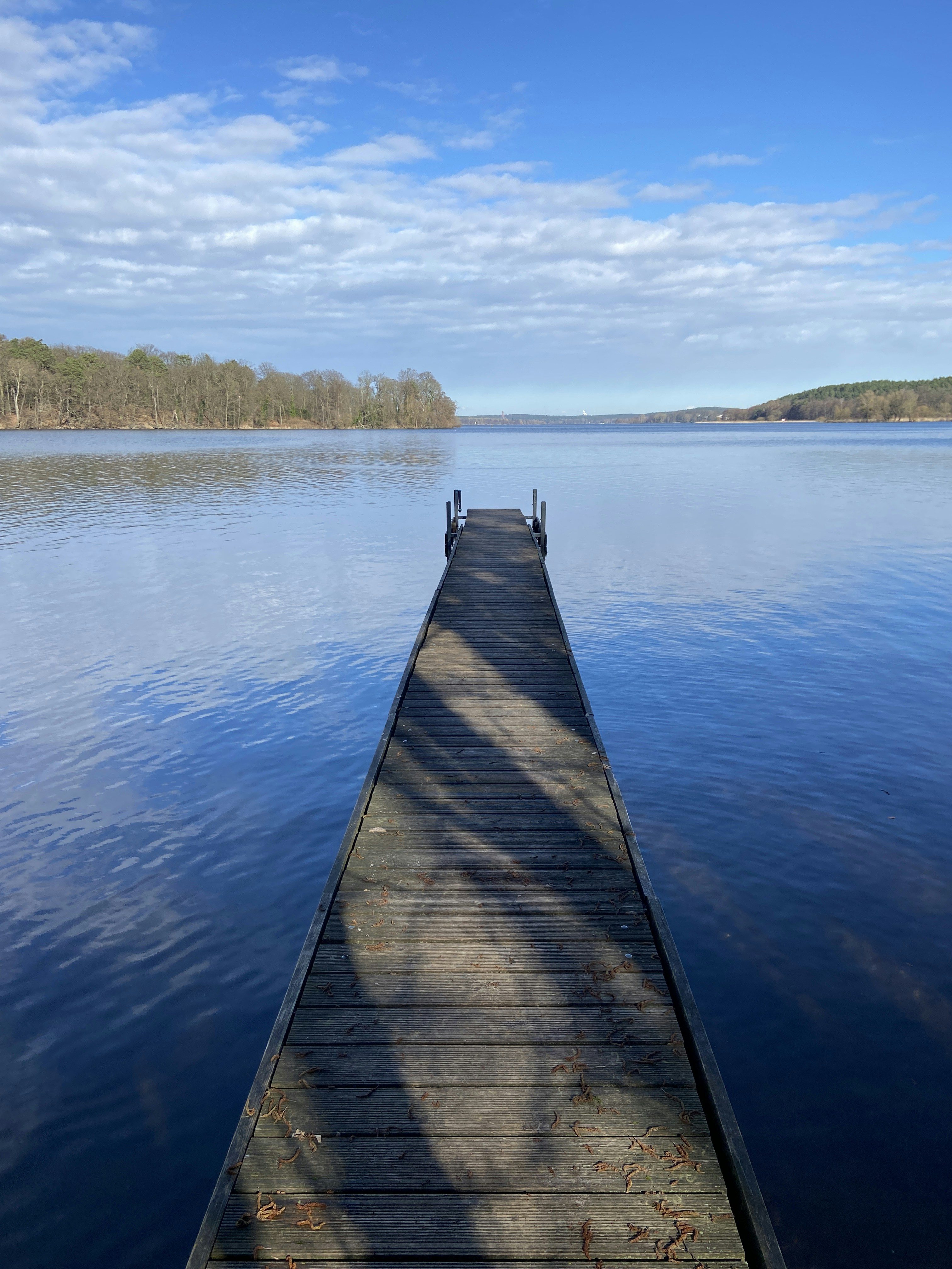 A dock on a lake with a long shadow on the water photo – Free Blue ...