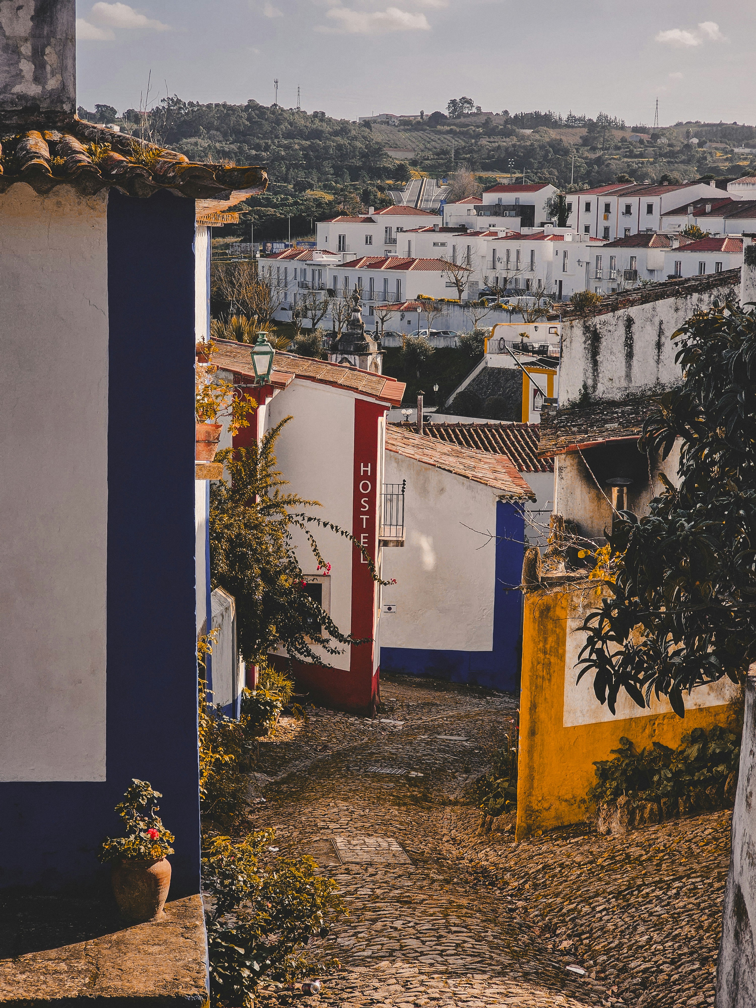 Cobbled Calle: A Red Hostel Gate Anchoring a Sunlit Whitewashed Quarter