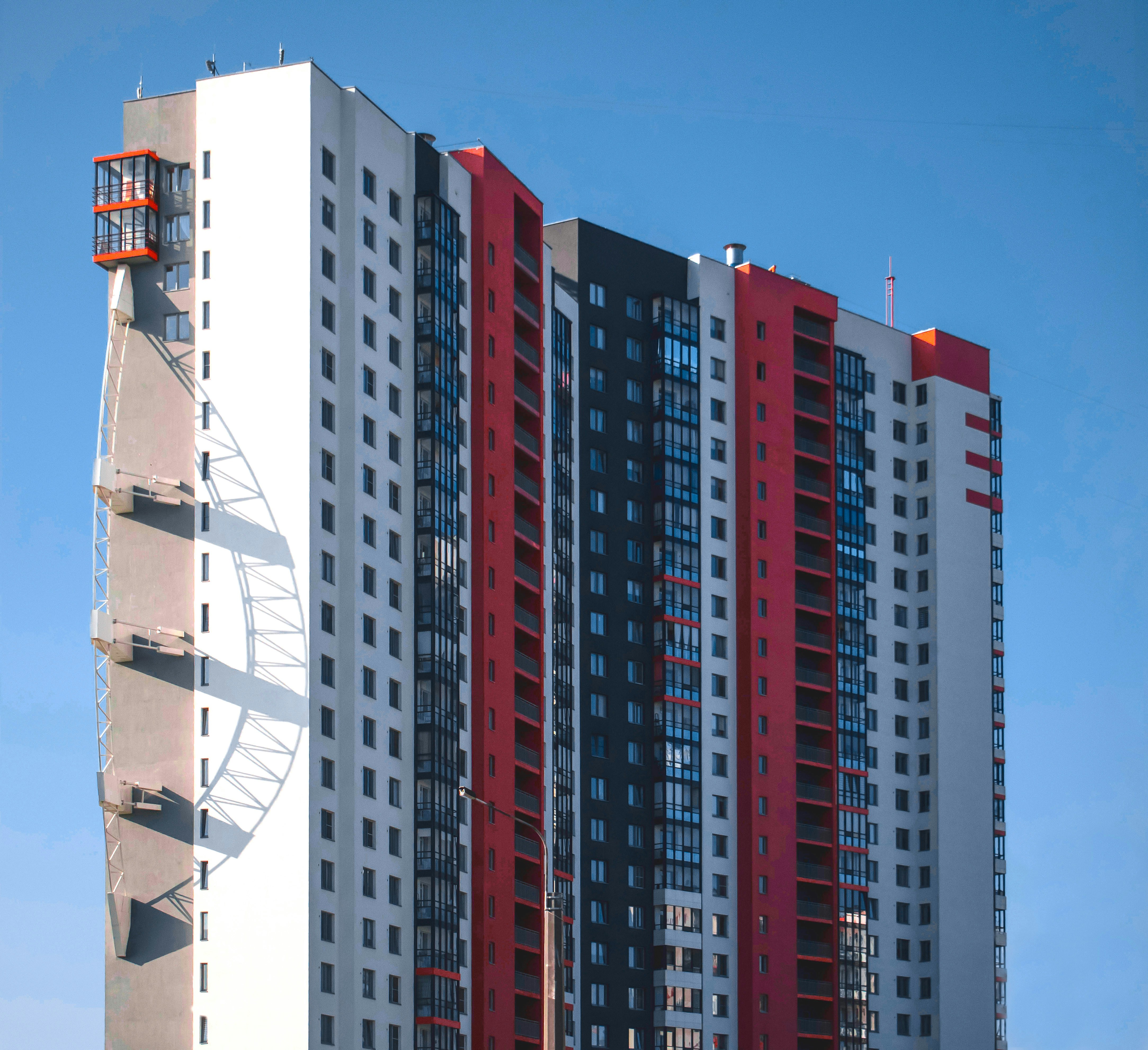 A tall white and red building next to a ferris wheel photo – Free ...