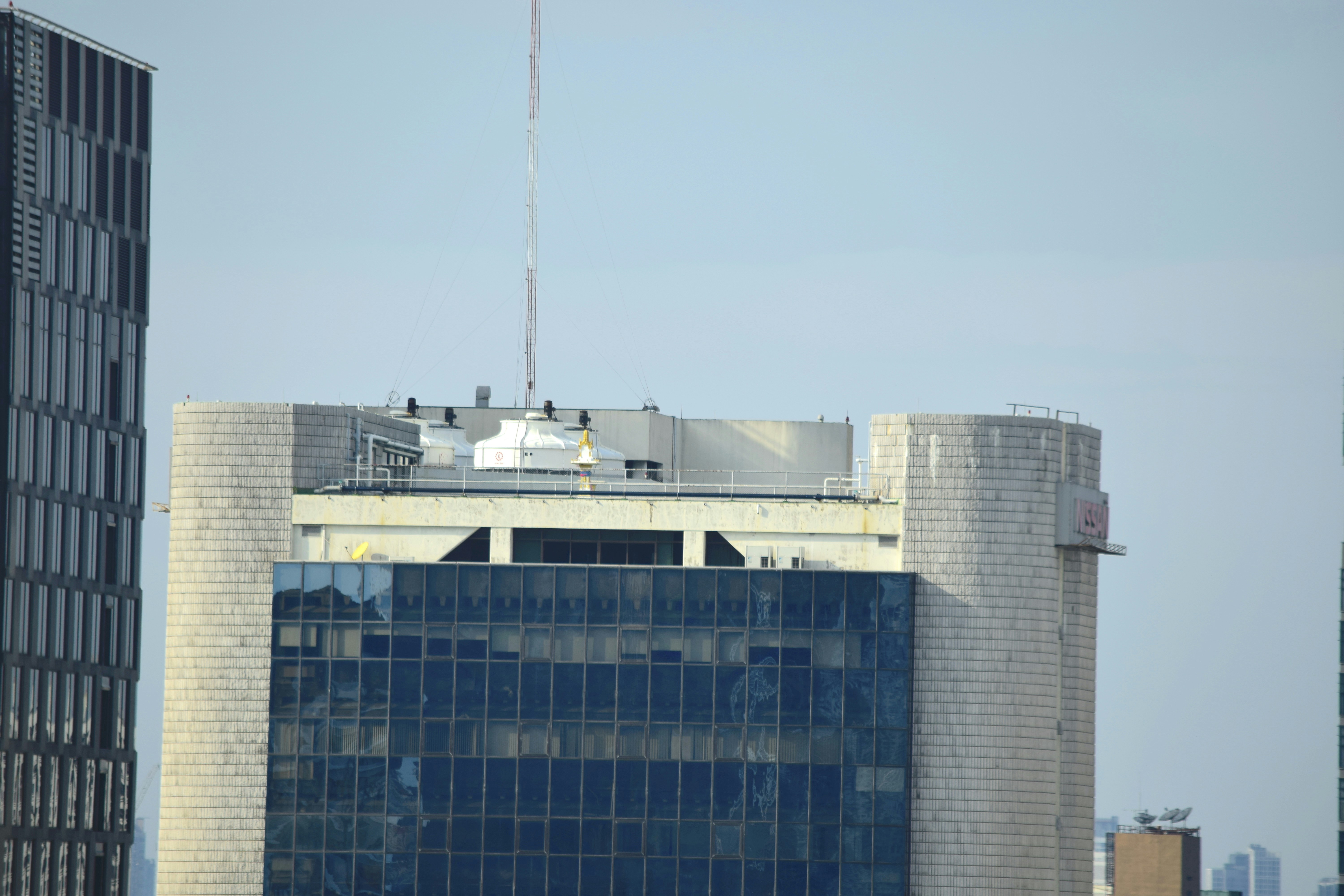 Rooftop Glassfront: Antennas and Skyline Against a Quiet Blue Sky