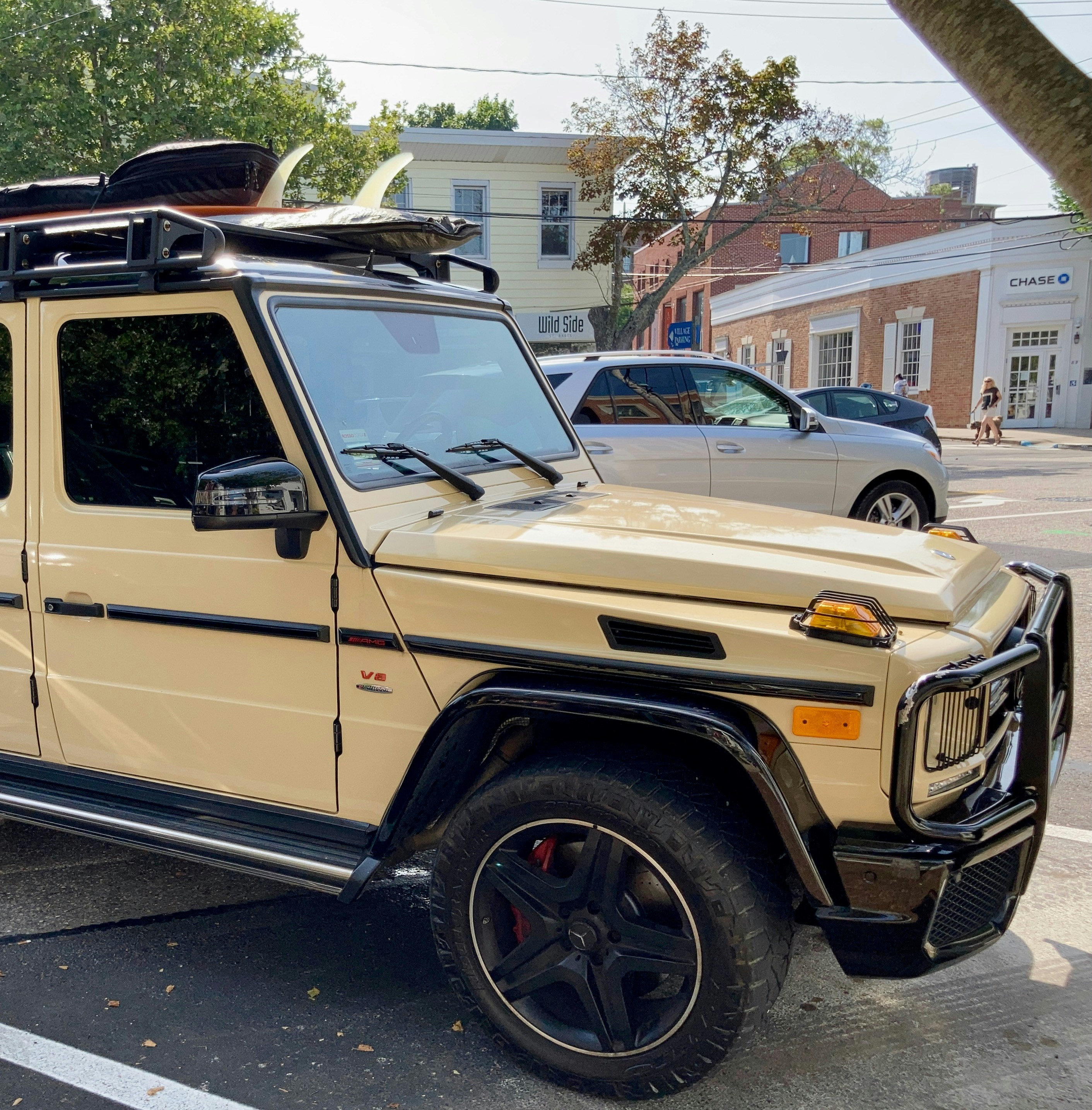 Beige G-Class on a Sunlit Main Street with Surfboard Rack
