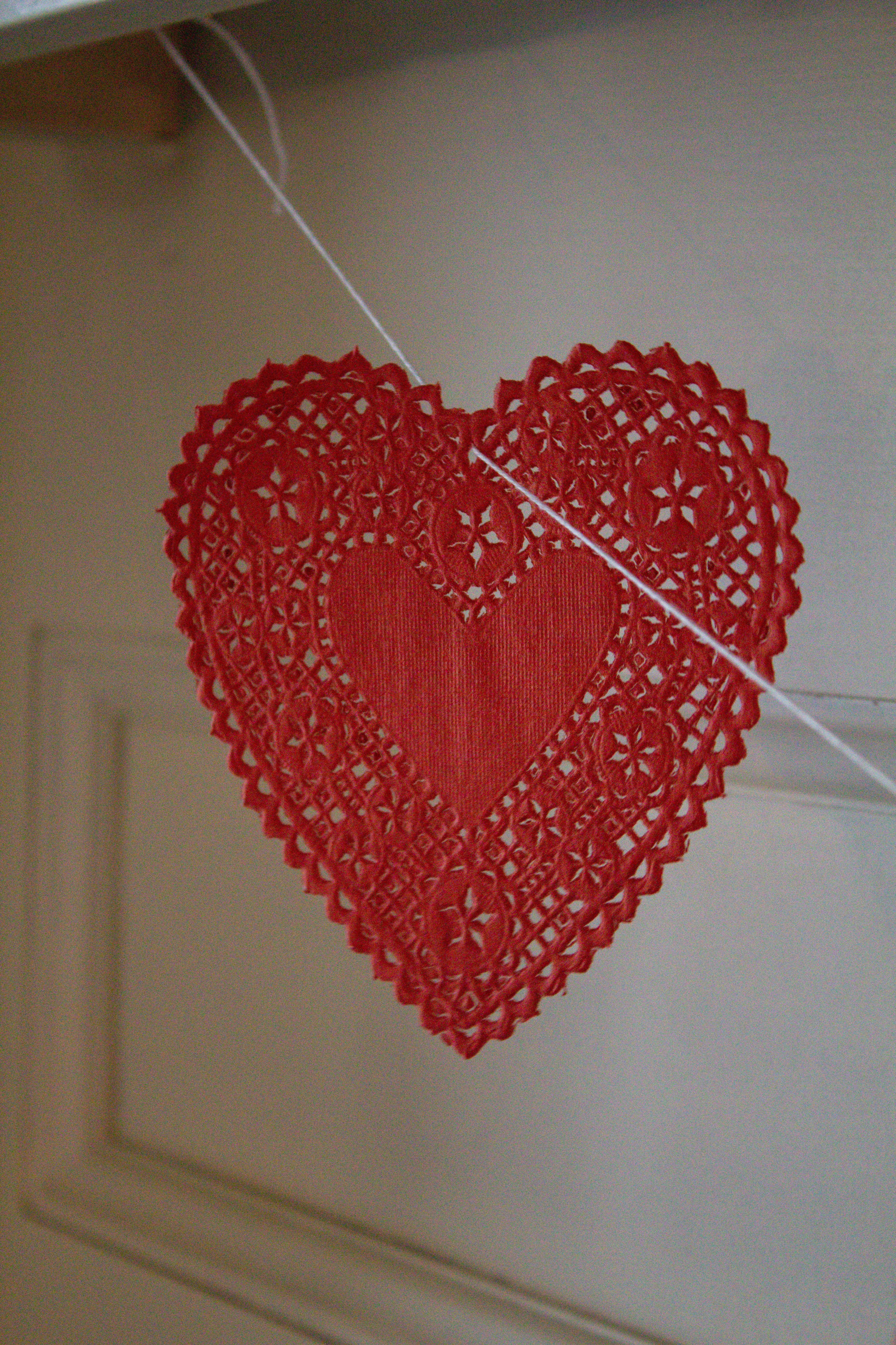 Suspended Crimson Lace Heart: a delicate centerpiece against a pale wall