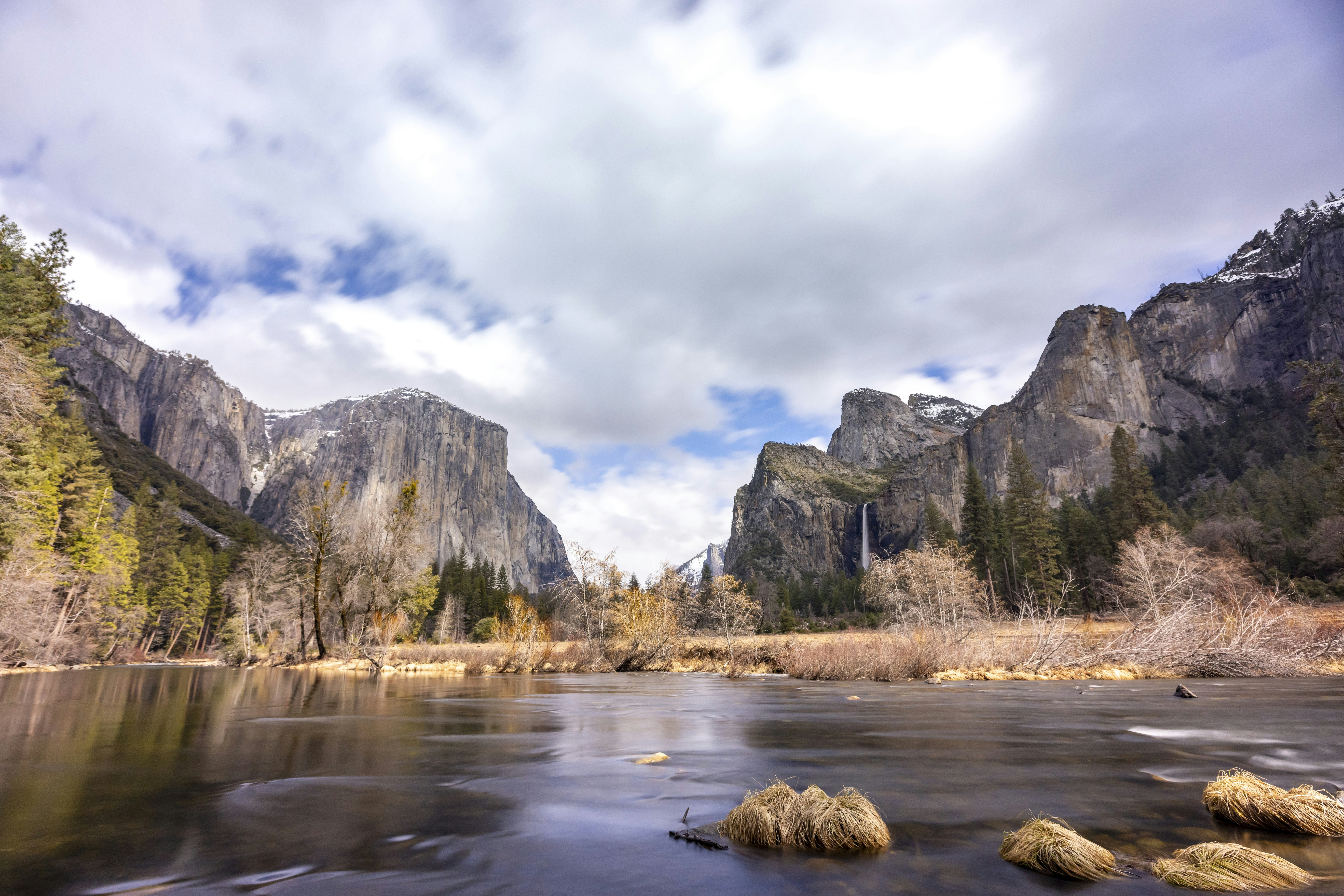A river surrounded by mountains under a cloudy sky photo – Free ...