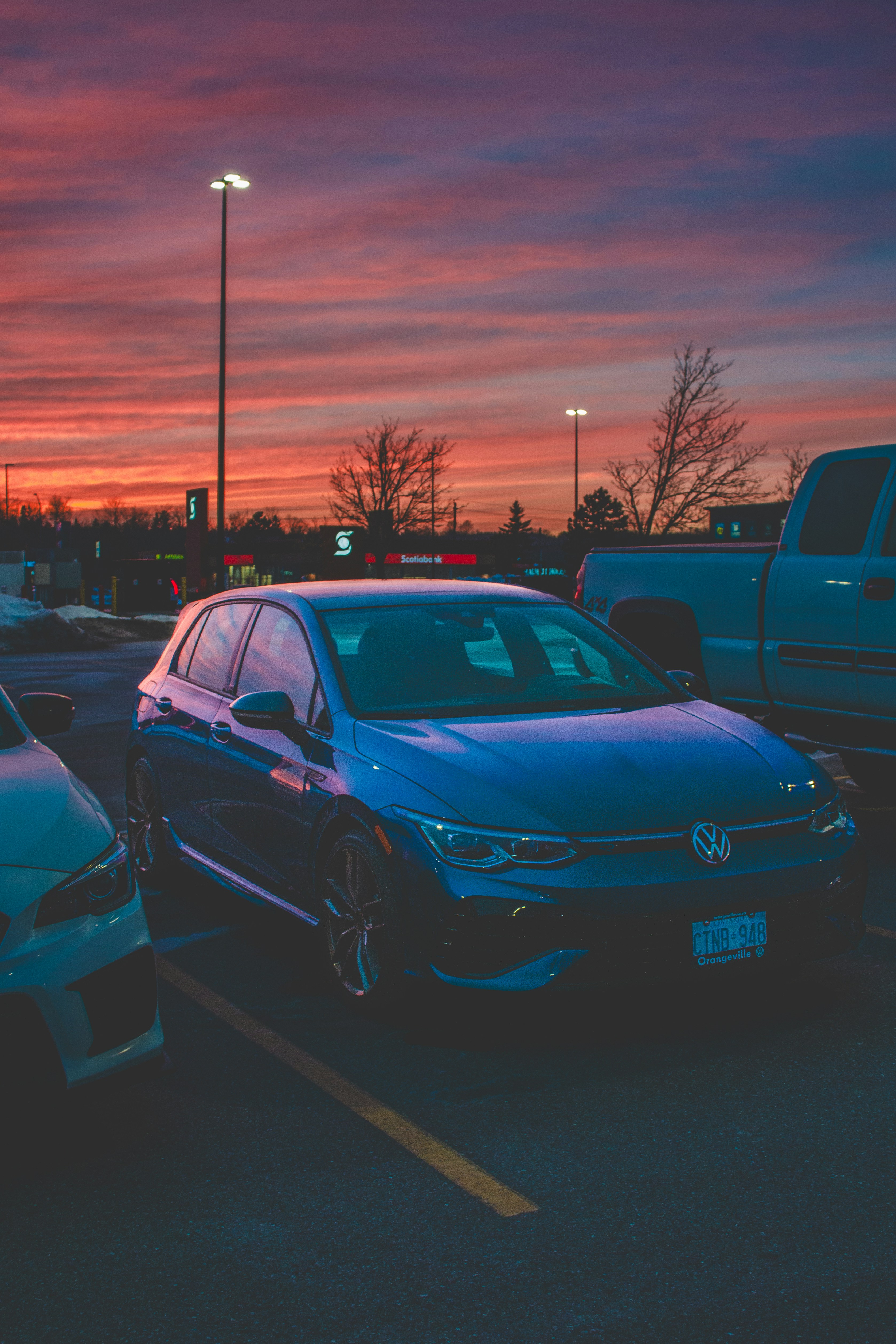 Amber Hour: Blue VW Under a Painted Sunset in a Quiet Parking Lot