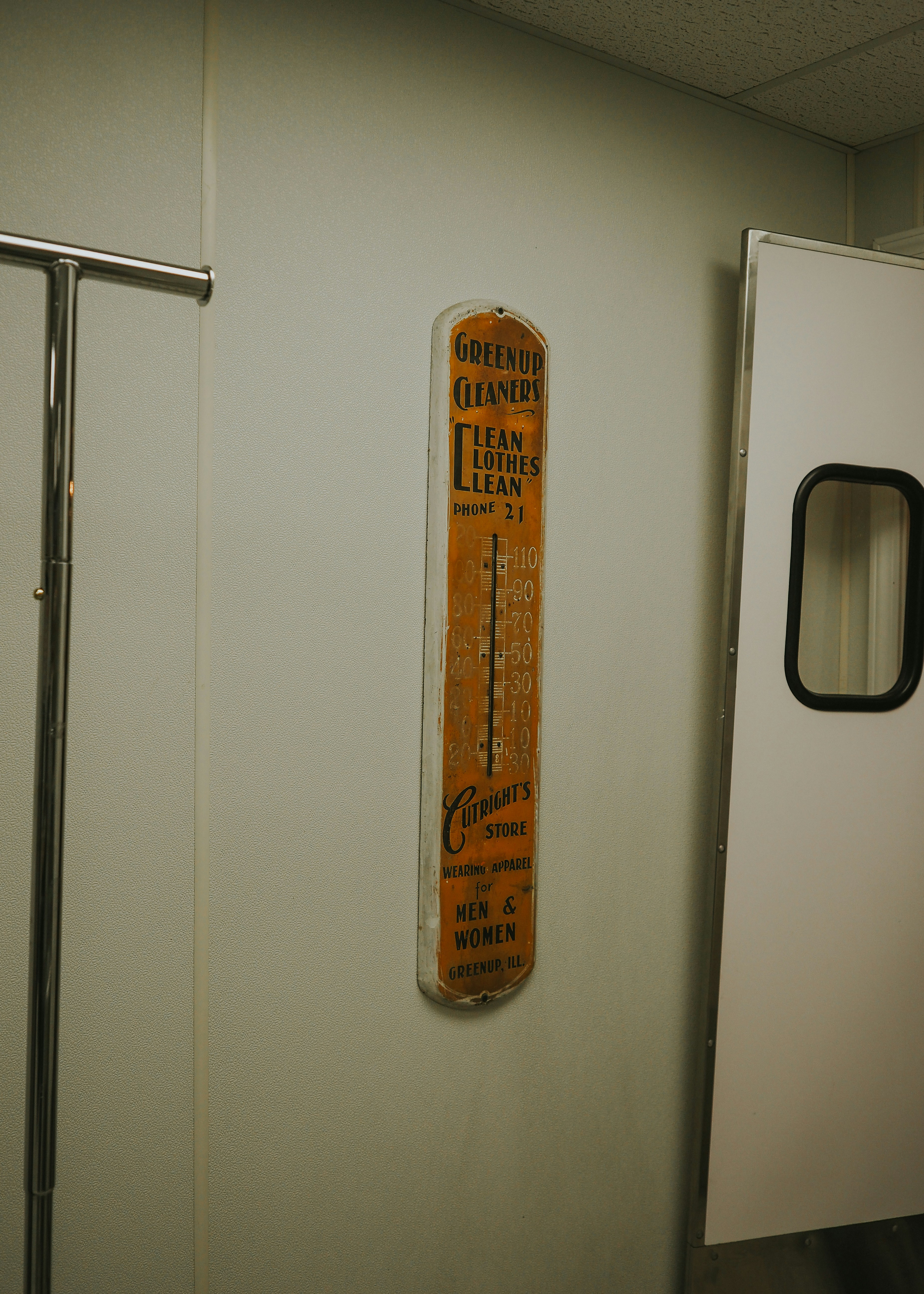 Timeworn Thermometer Ad on a Quiet Transit Wall
