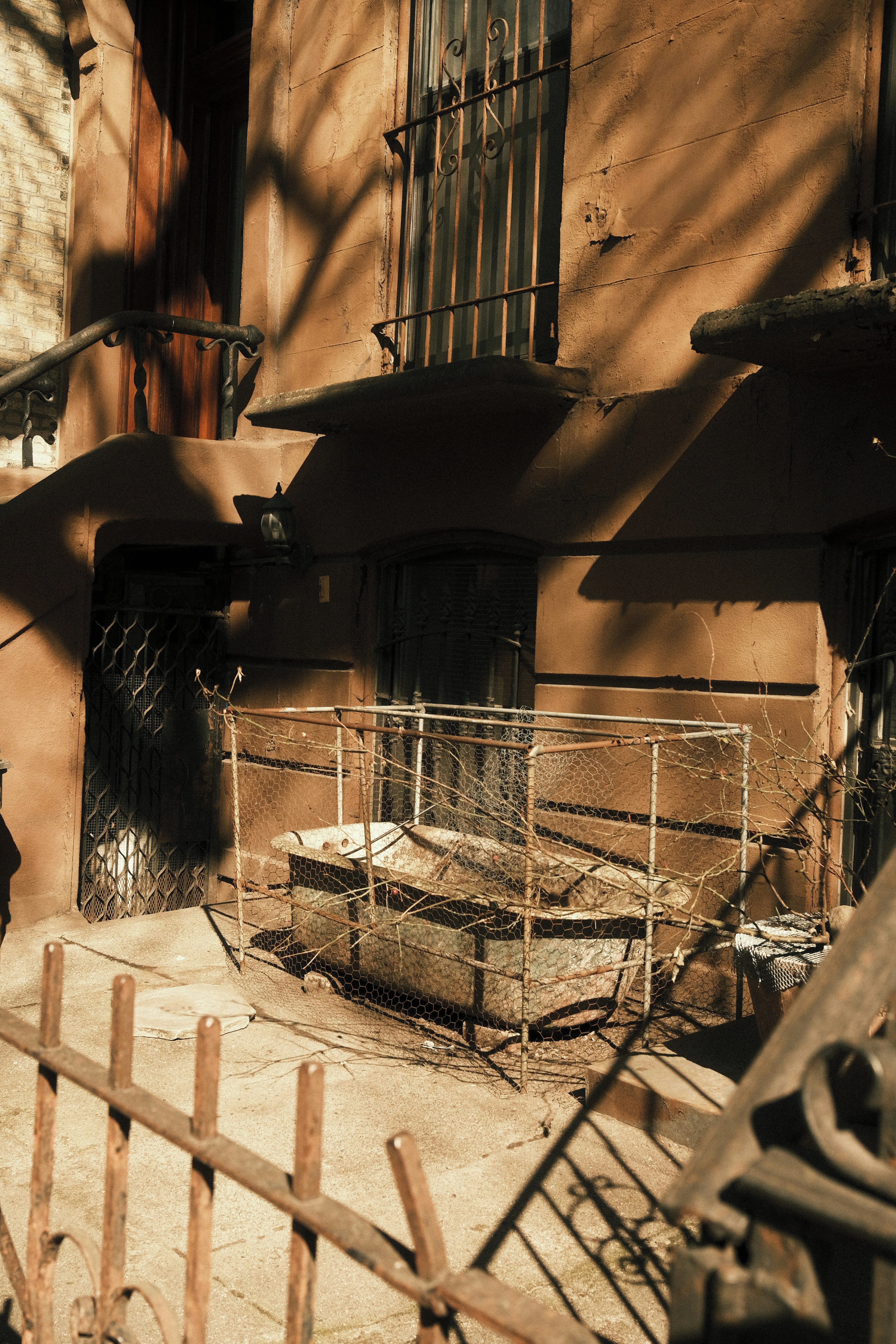 Sun-Scarred Courtyard: Rust, Shadow, and a Wrought Fence