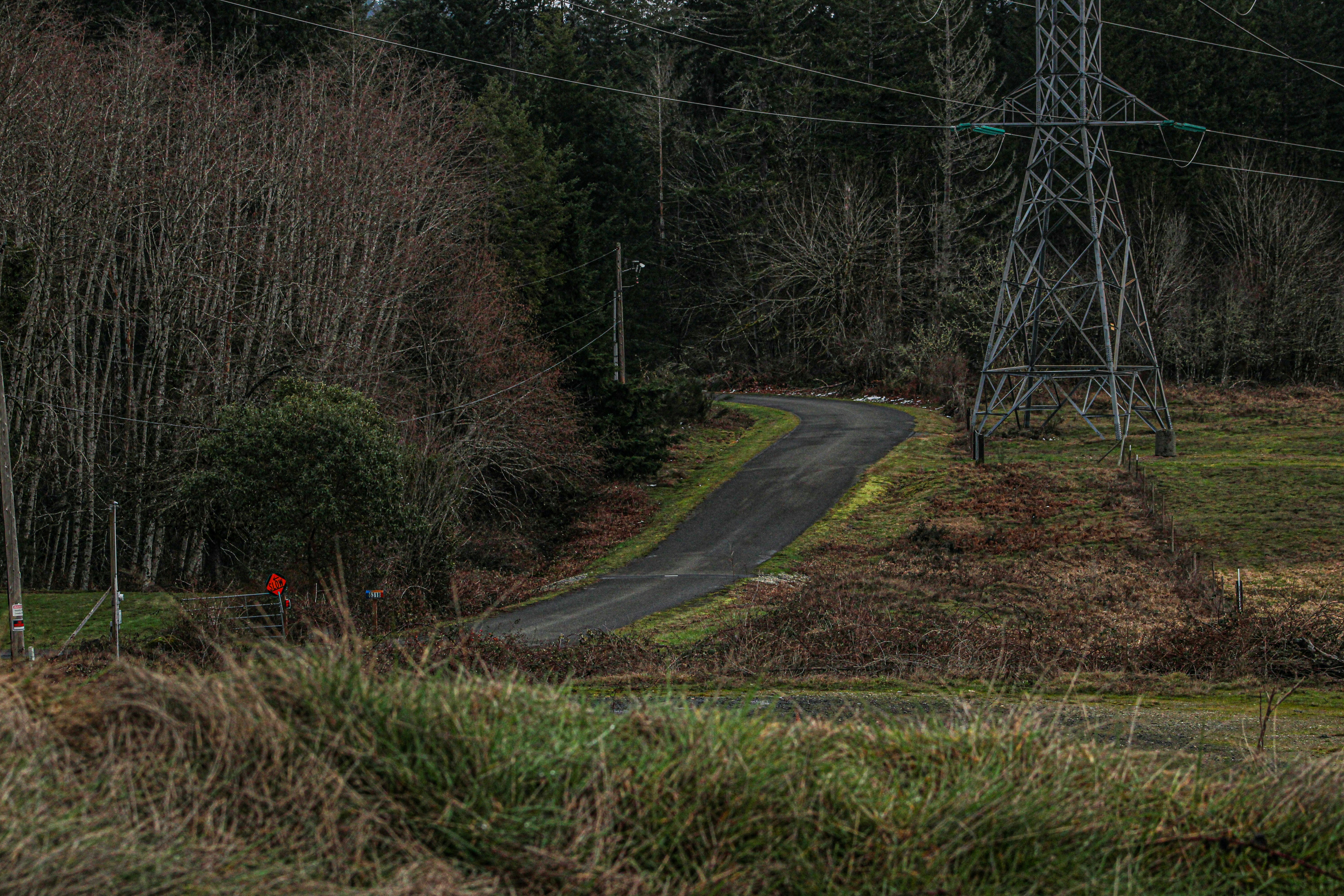 Rural Road Bends Around a Power Line Tower