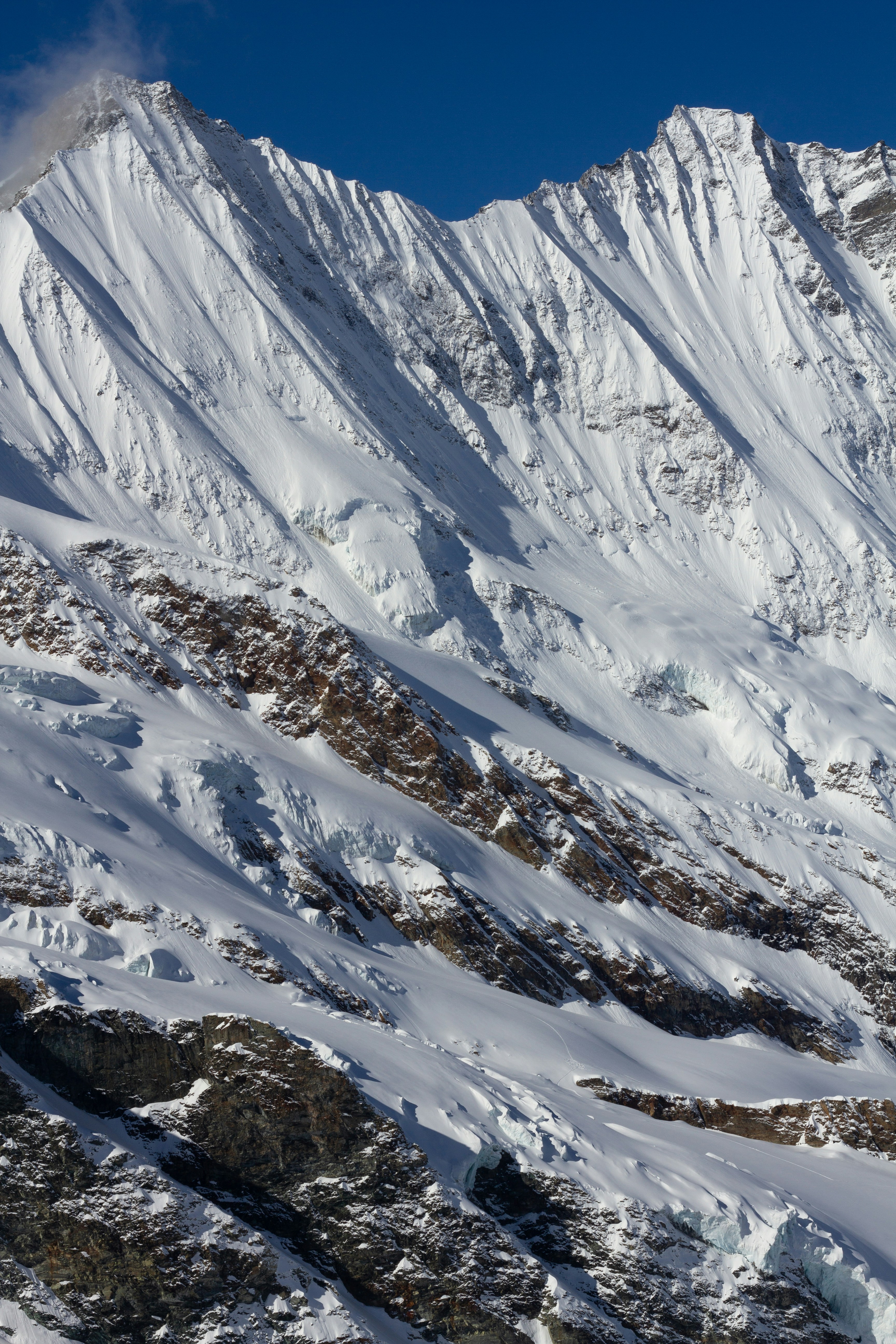 Majestic snow-covered mountain range with intricate ridges and valleys, showcasing the raw beauty of nature's winter landscape.