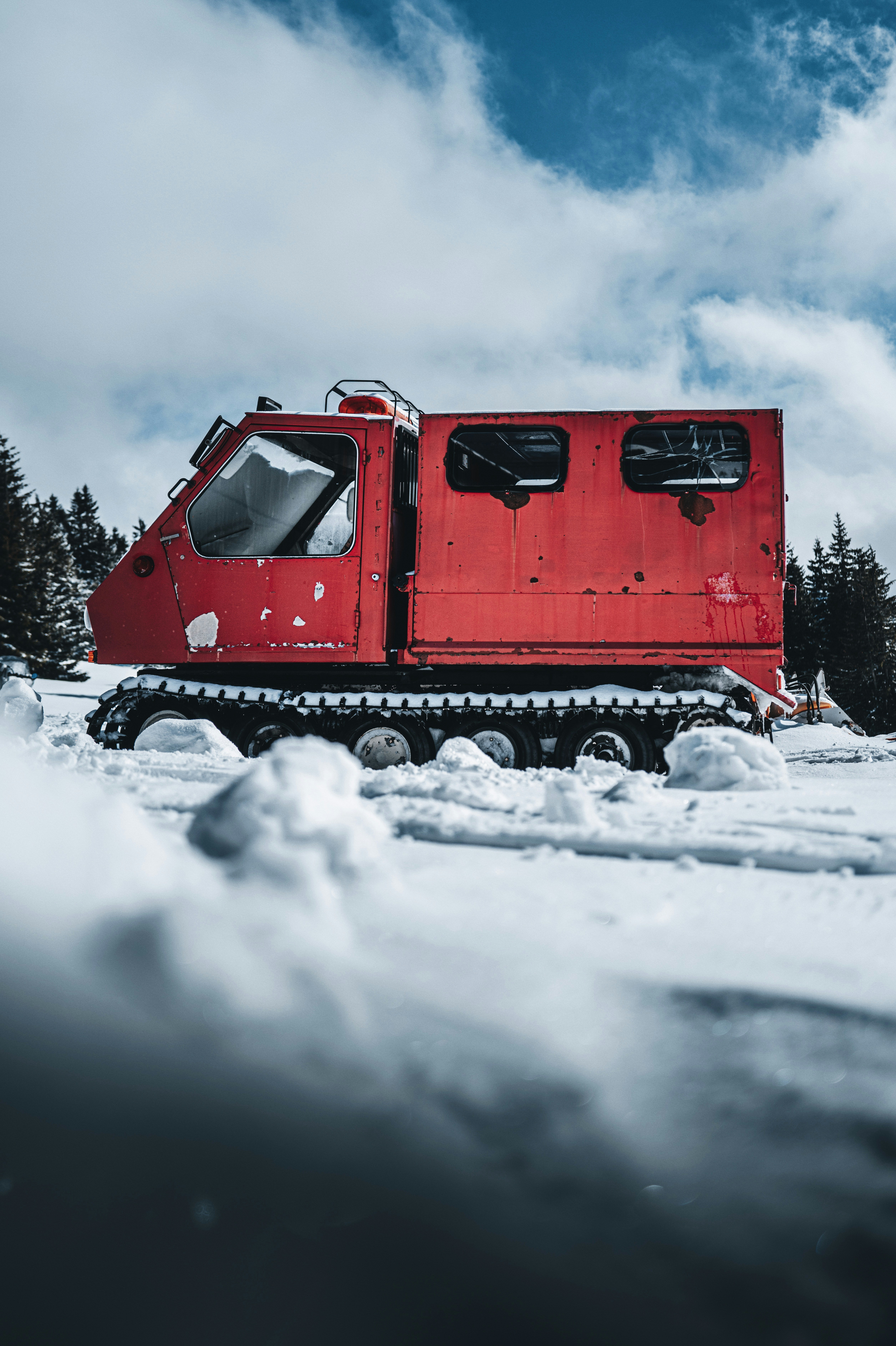 Crimson Snowcat on a Snowy Ridge Under a Blue Winter Sky