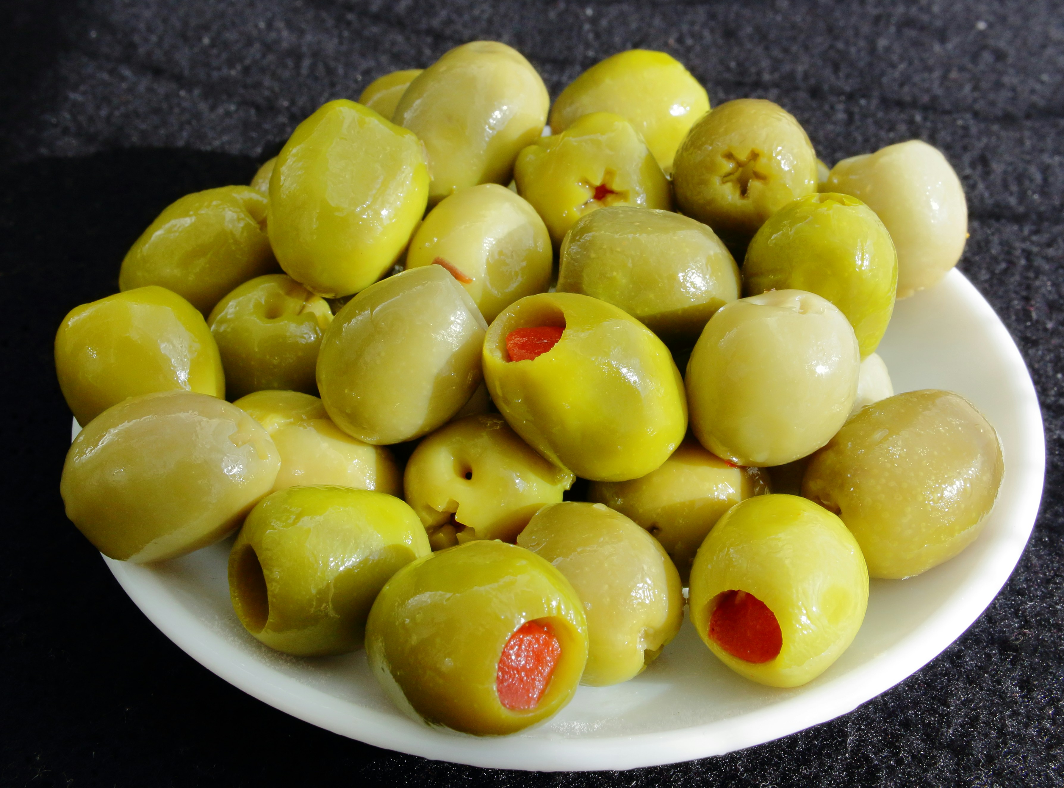 A white plate filled with green olives on a table photo – Free Olive ...