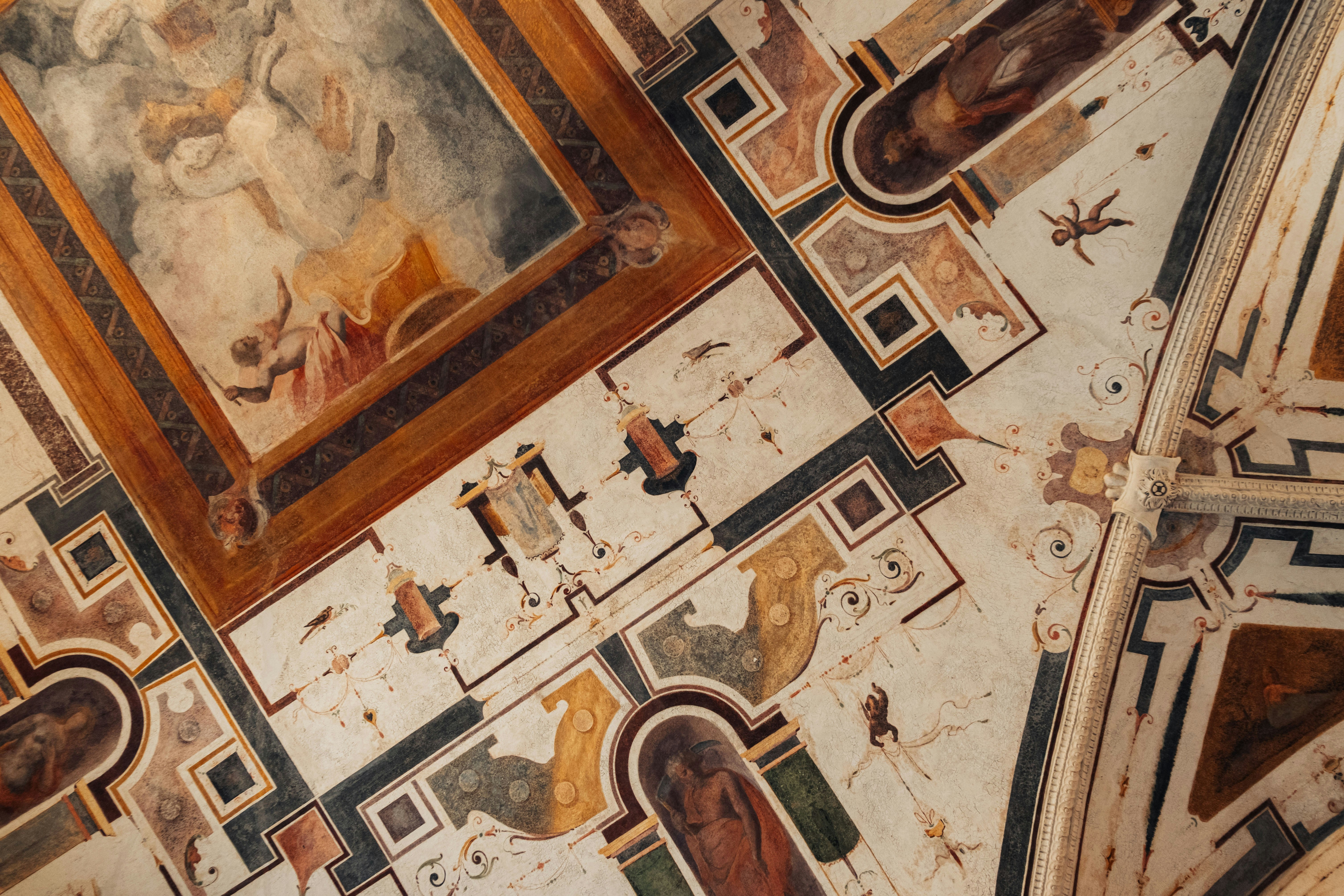 Ornate ceiling with detailed frescoes and geometric designs in a historic building.