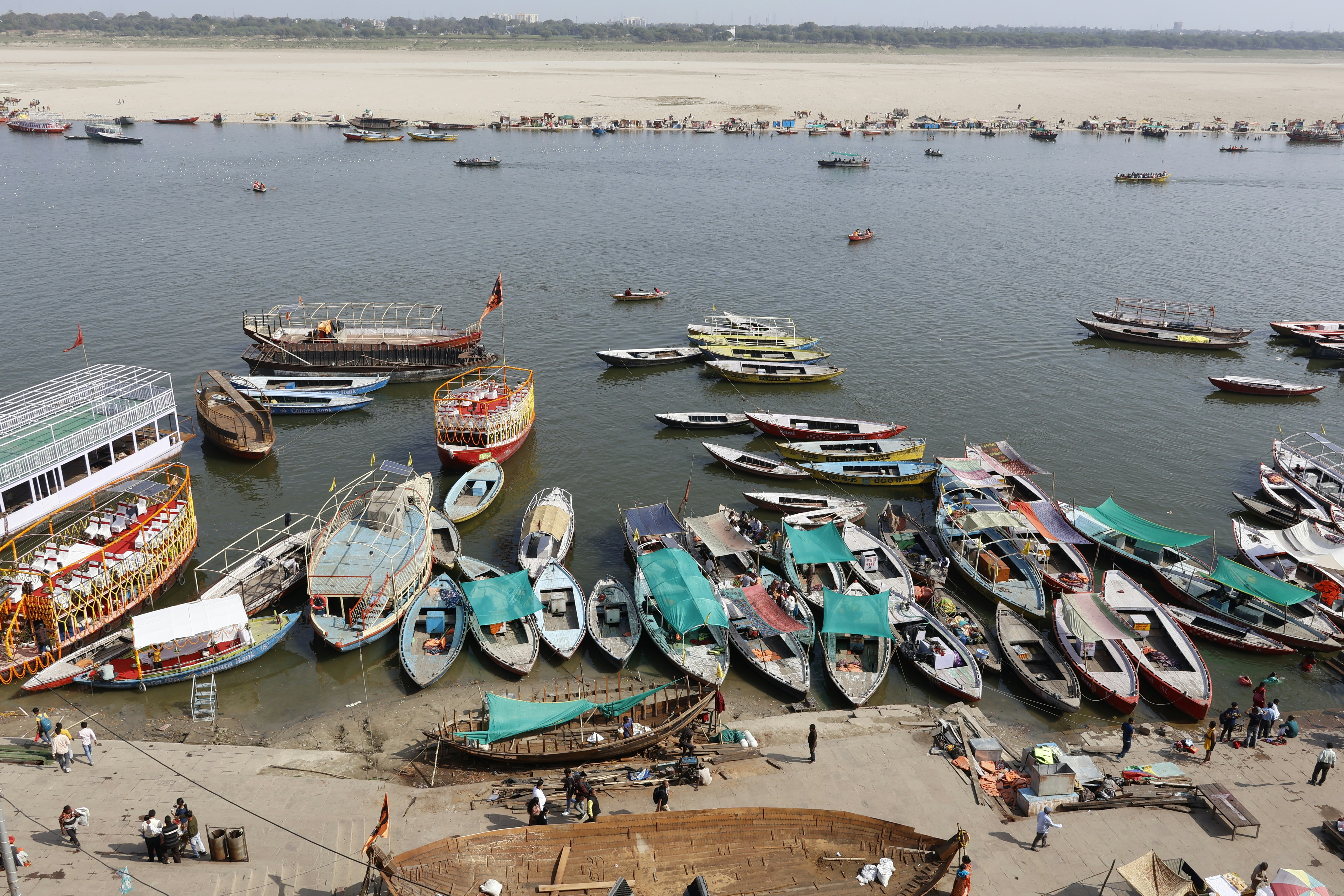 A vibrant assembly of boats docked along a riverbank, showcasing a blend of colors and activity. The scene captures the essence of daily life by the water.