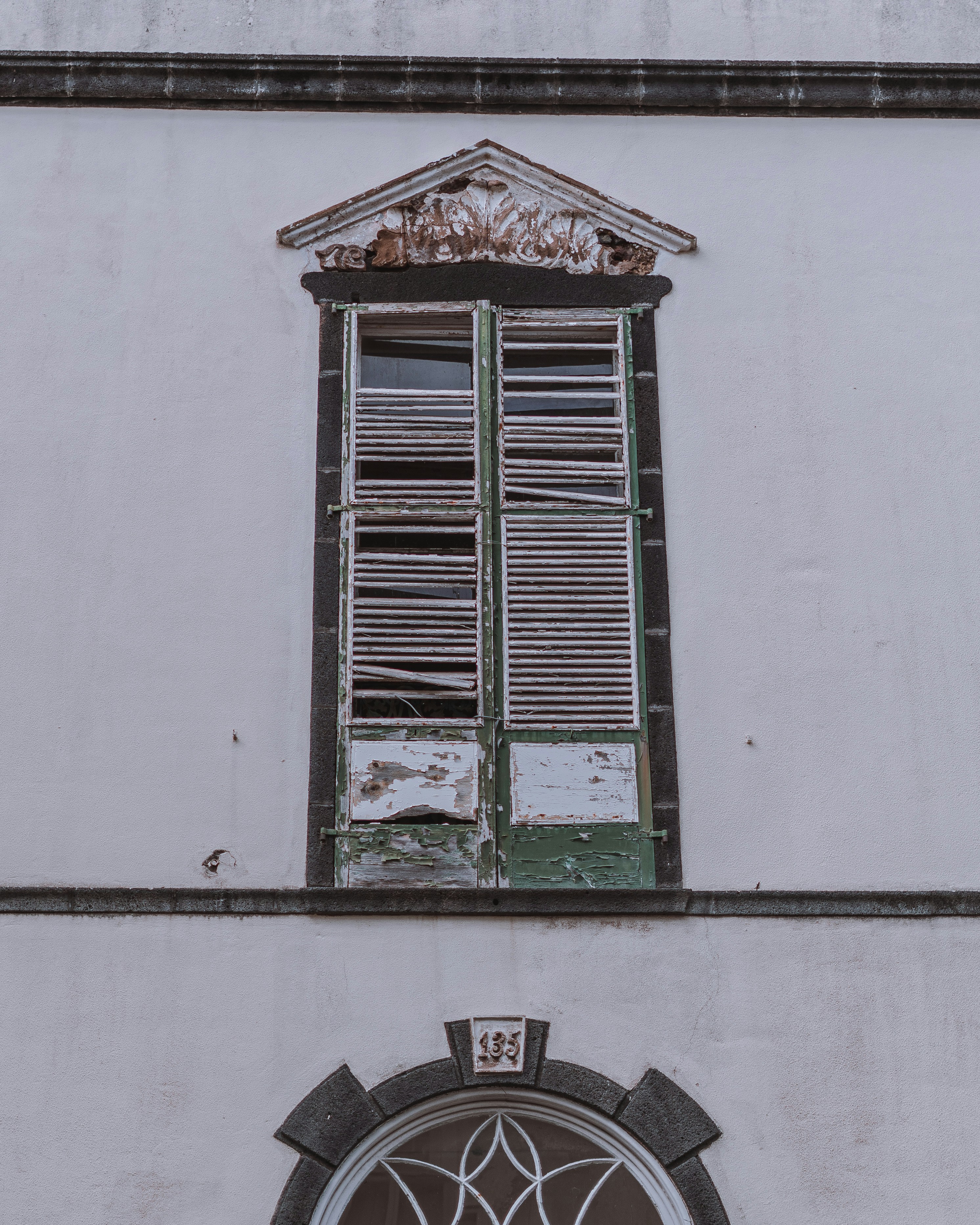 Peeling Green Window: Weathered Facade's Quiet Portrait