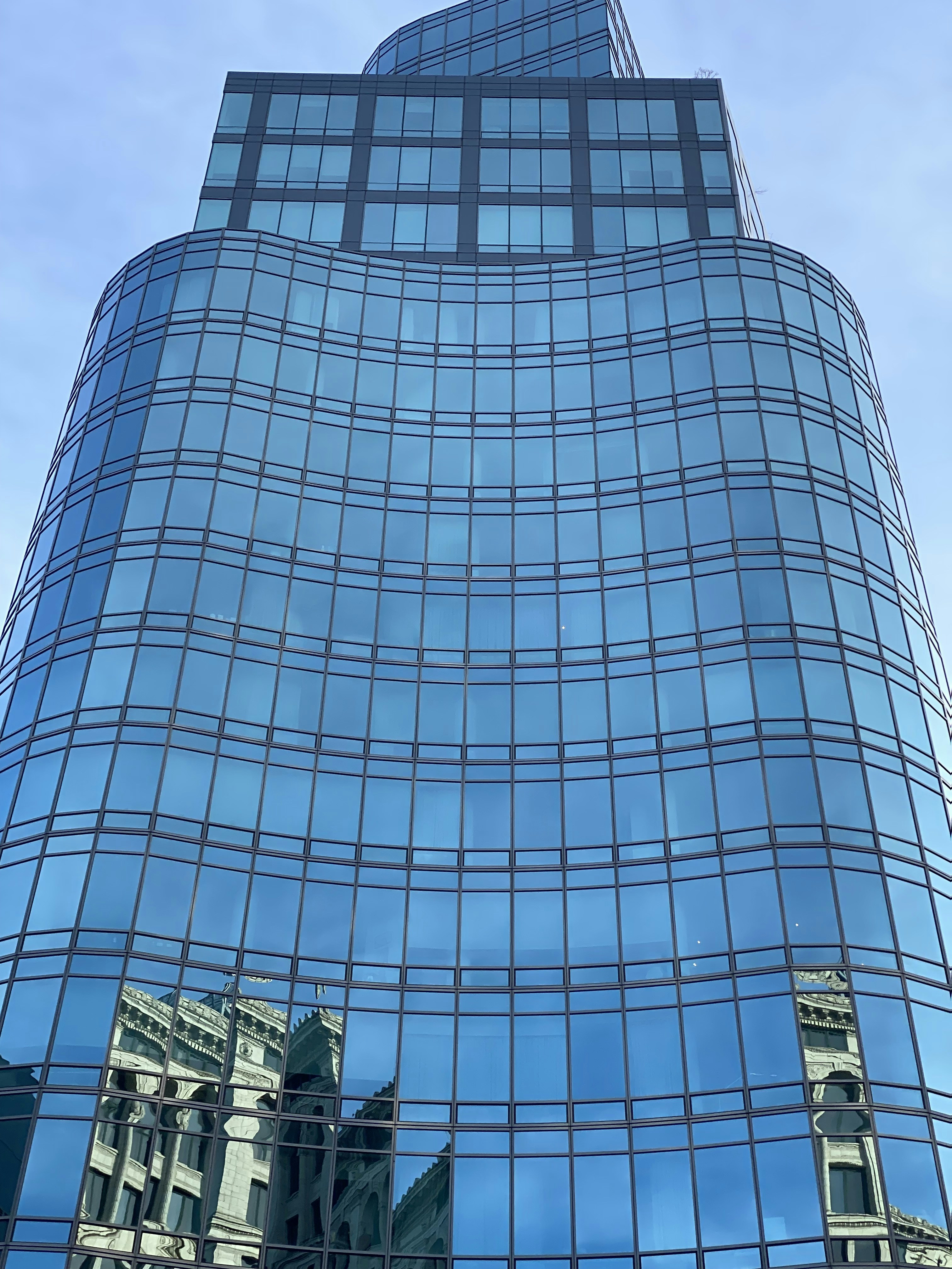 A very tall glass building with a clock on it's side photo – Free Blue ...