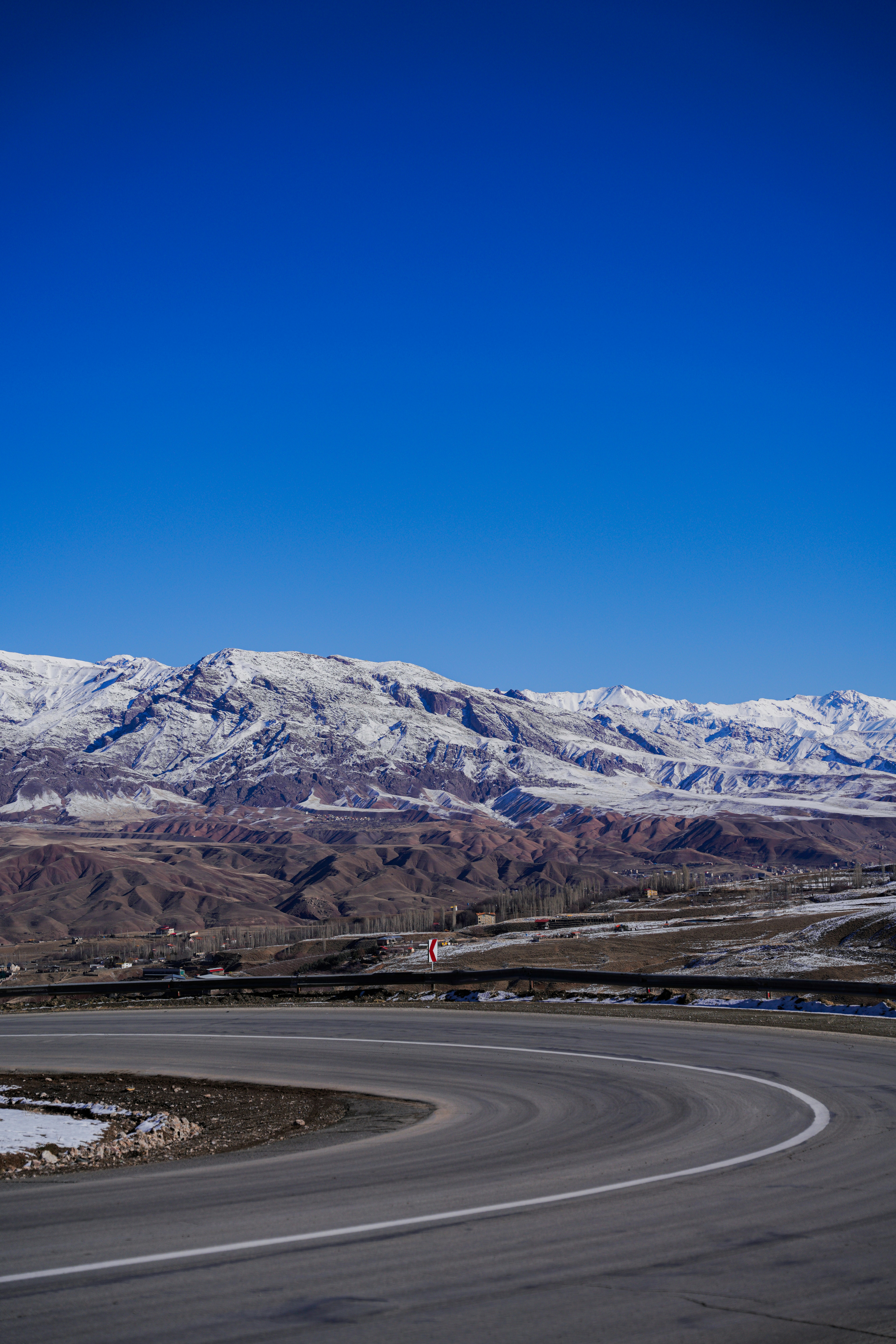 A curved road with snow covered mountains in the background photo ...