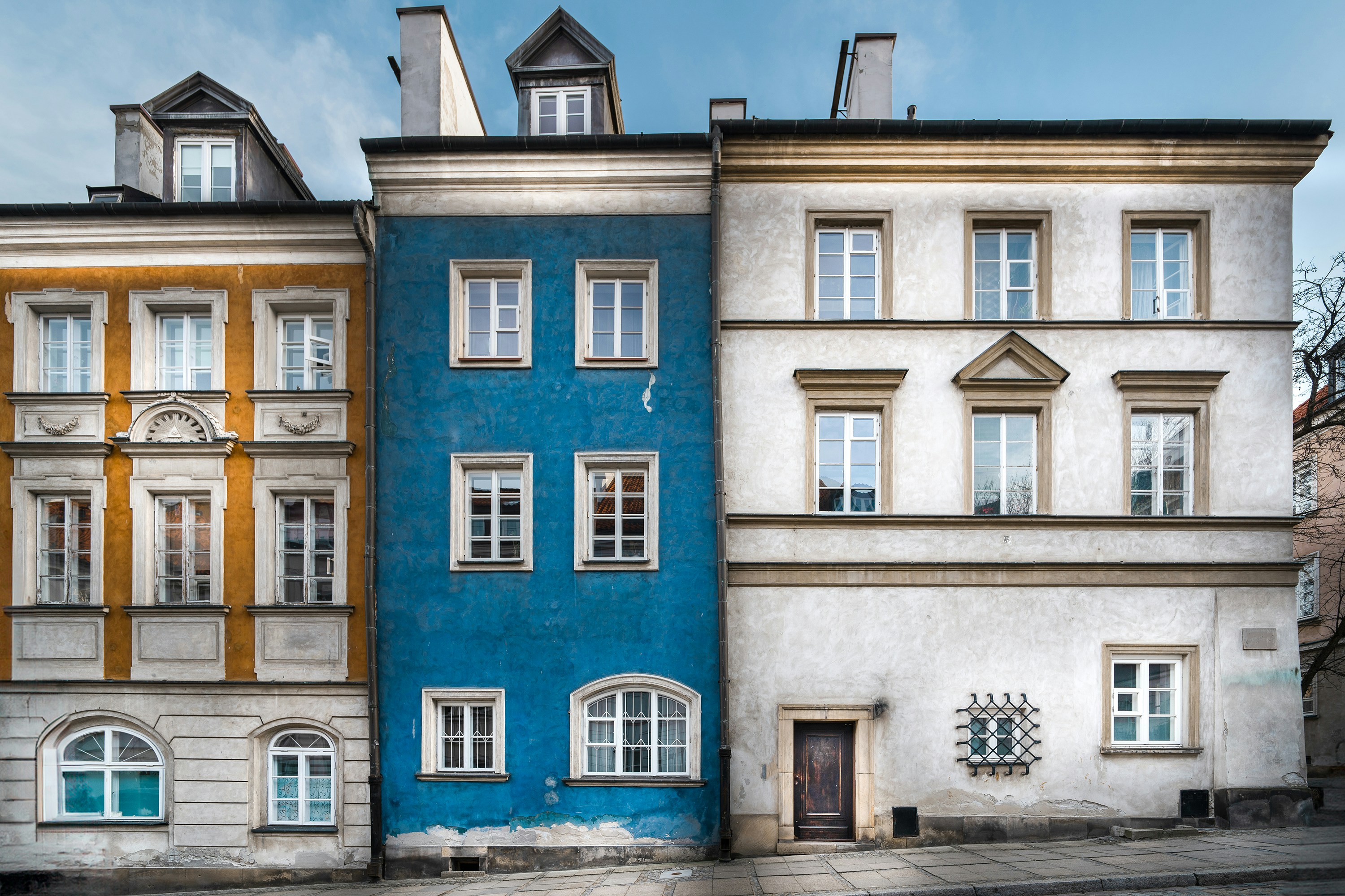 Three distinct buildings showcasing unique architectural styles and colors, with a focus on the vibrant blue facade. 