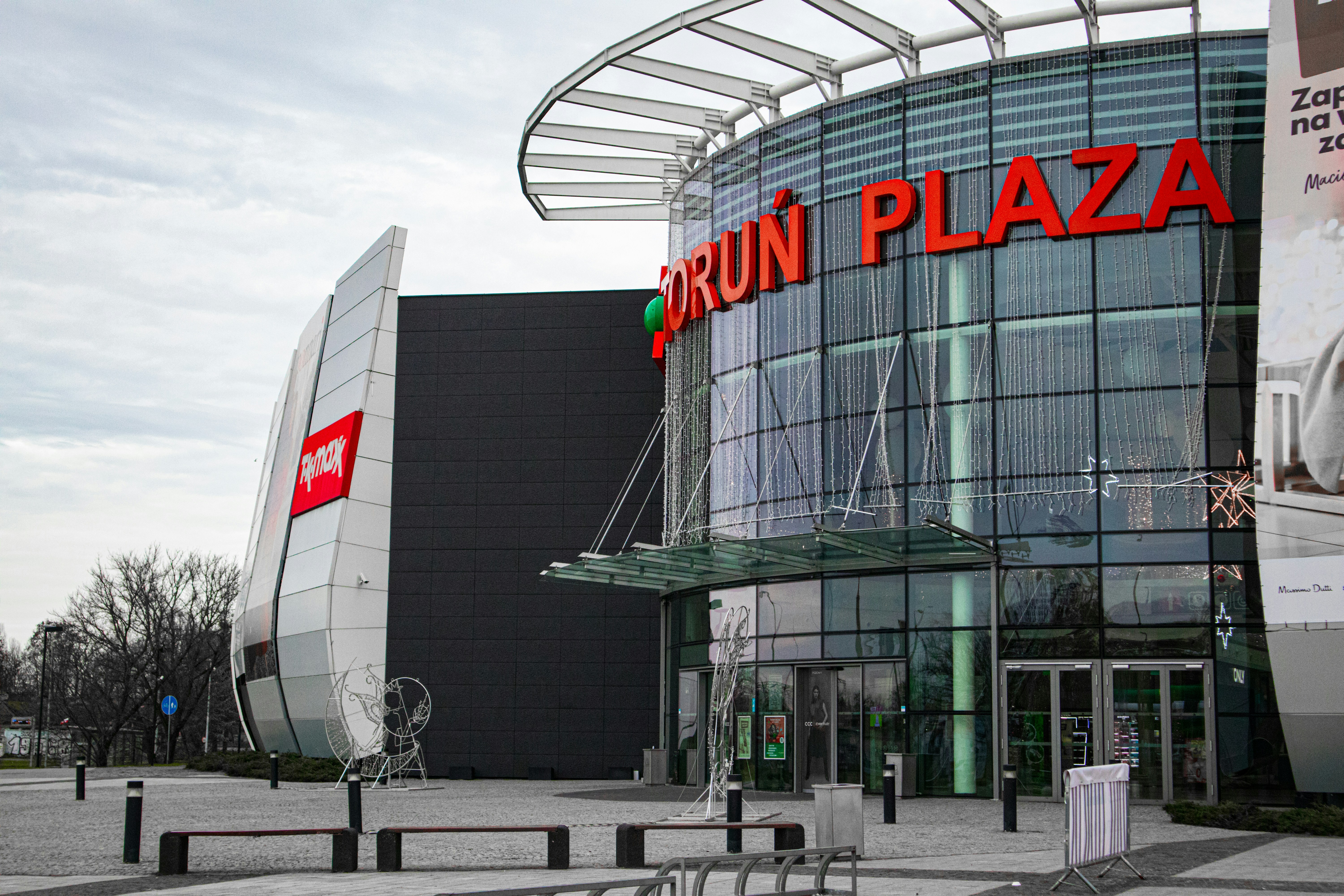 Contemporary glass building with bold red 'Iron Plaza' sign under a cloudy sky.
