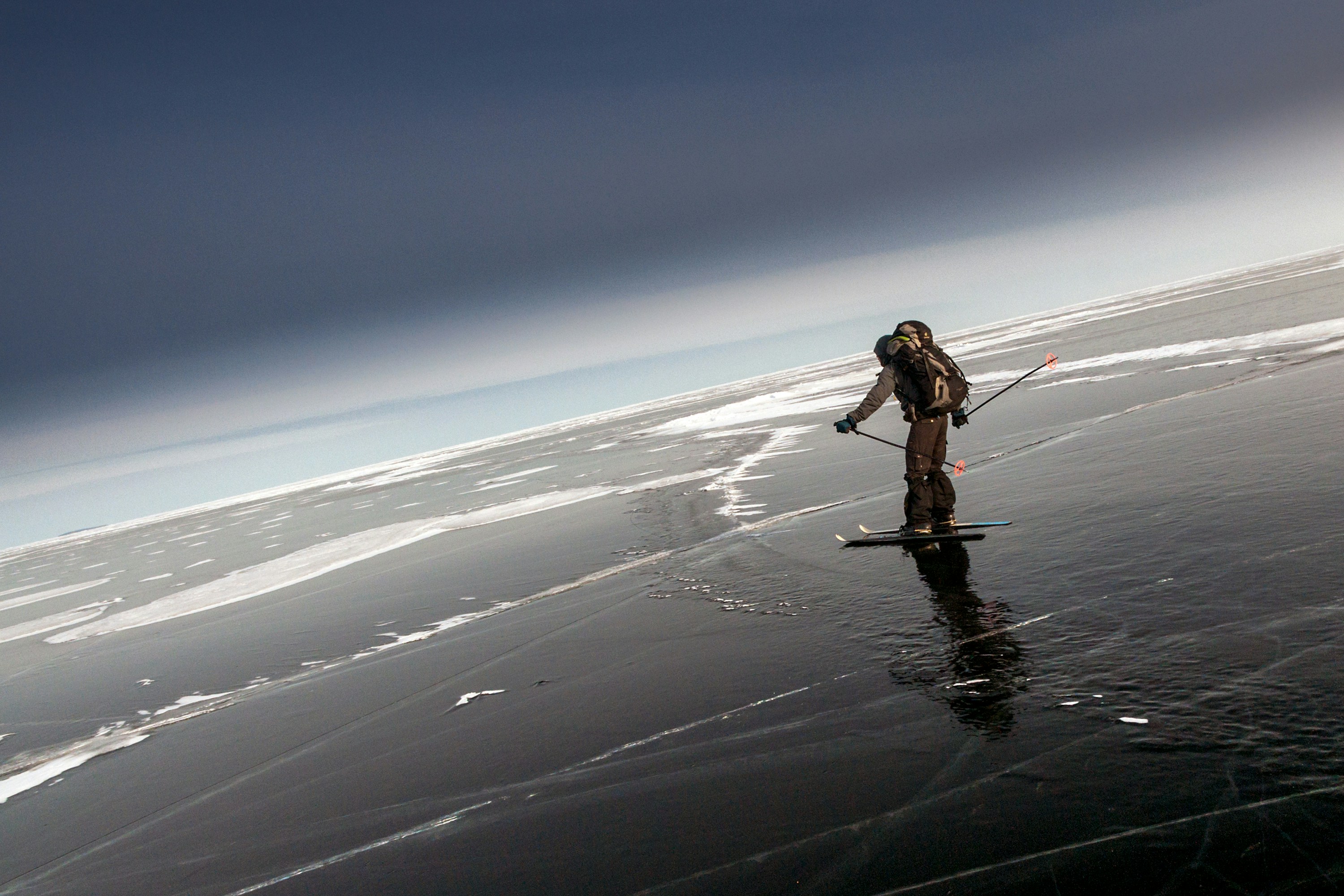 Glacial Glide: A Lone Explorer Traverses a Glassy Lake