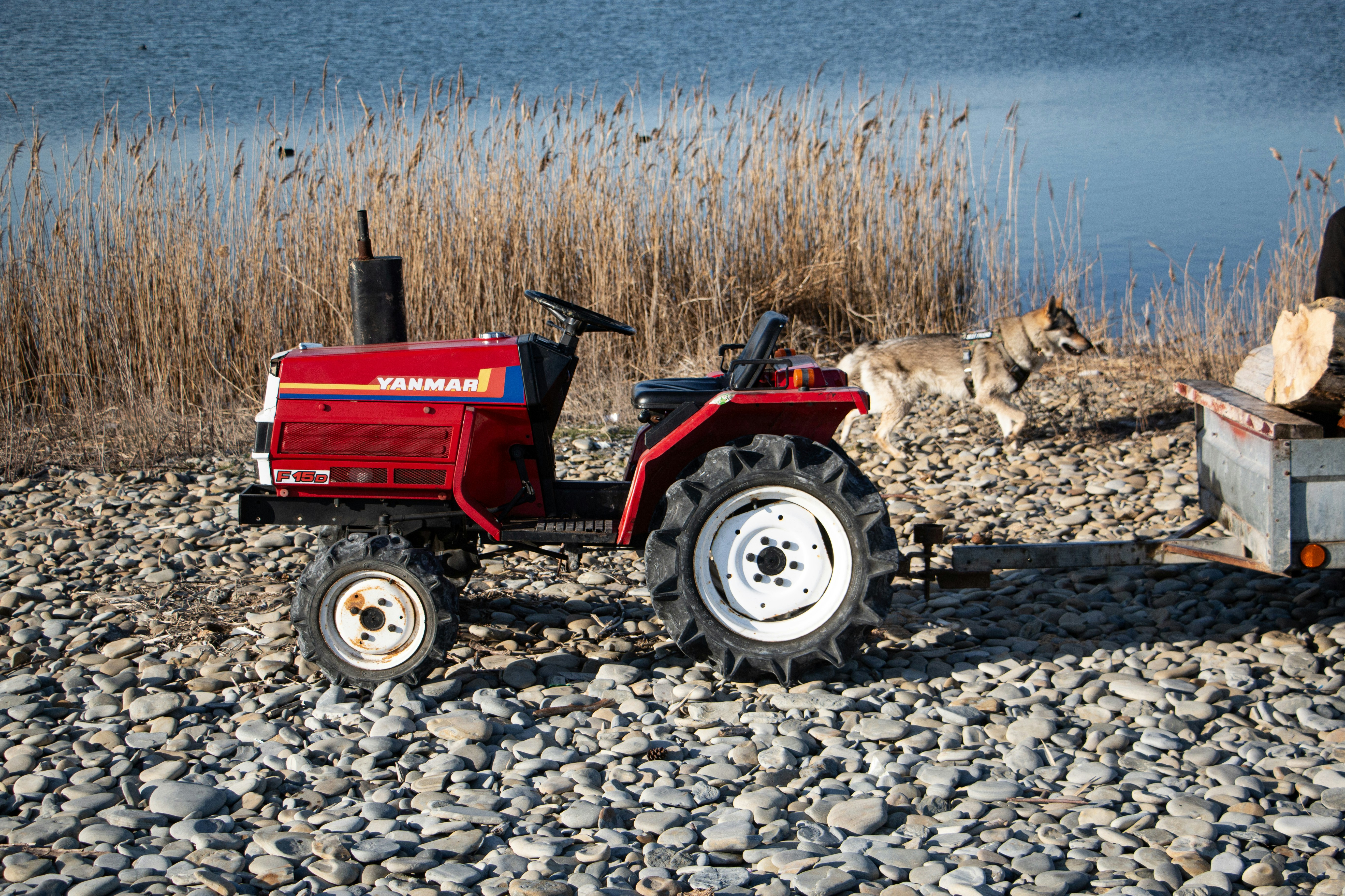 A red tractor parked next to a lake photo – Free Tractor Image on Unsplash
