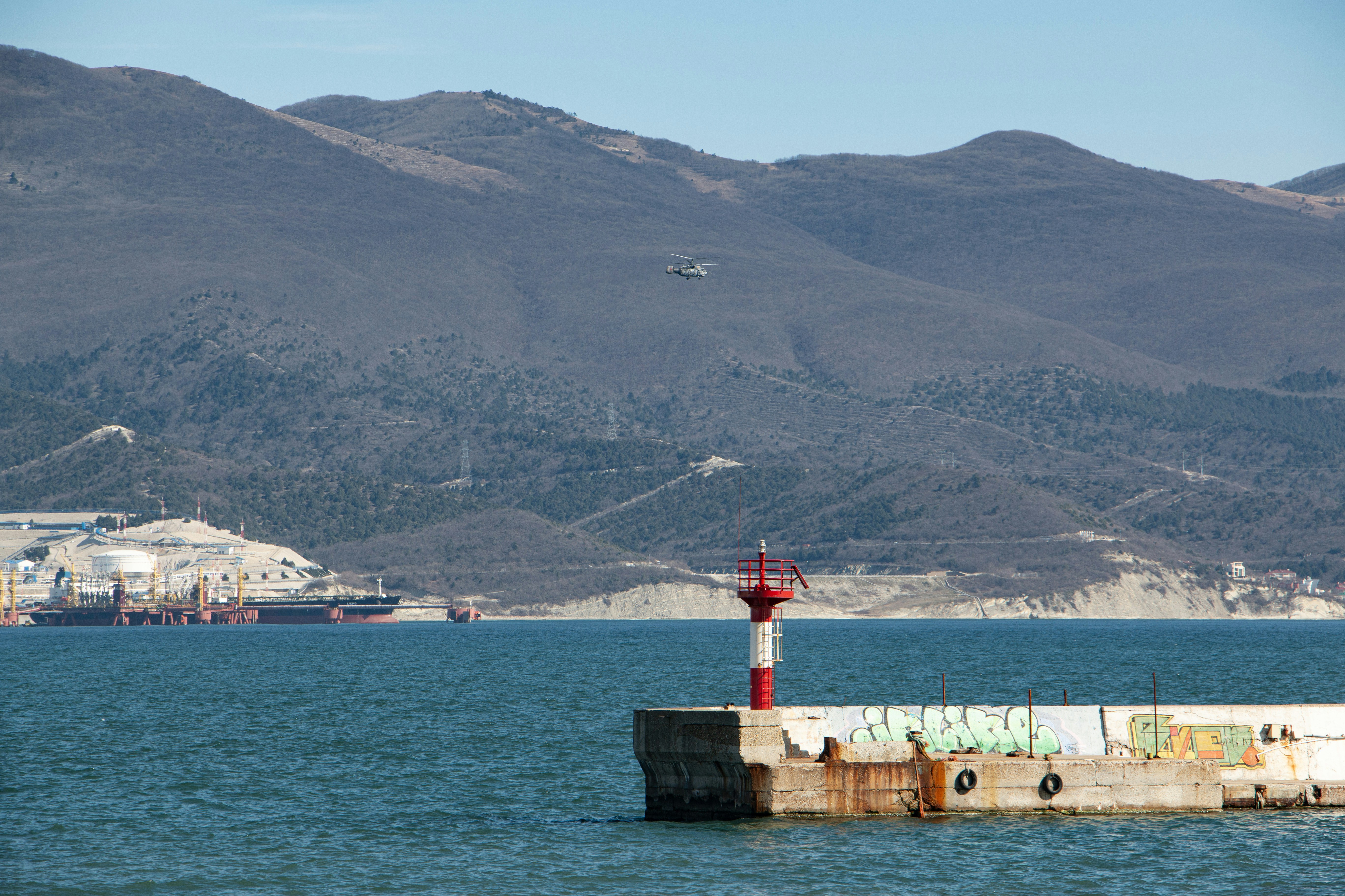 Crimson Beacon at the Breakwater: Harbor Edge Framed by Distant Hills