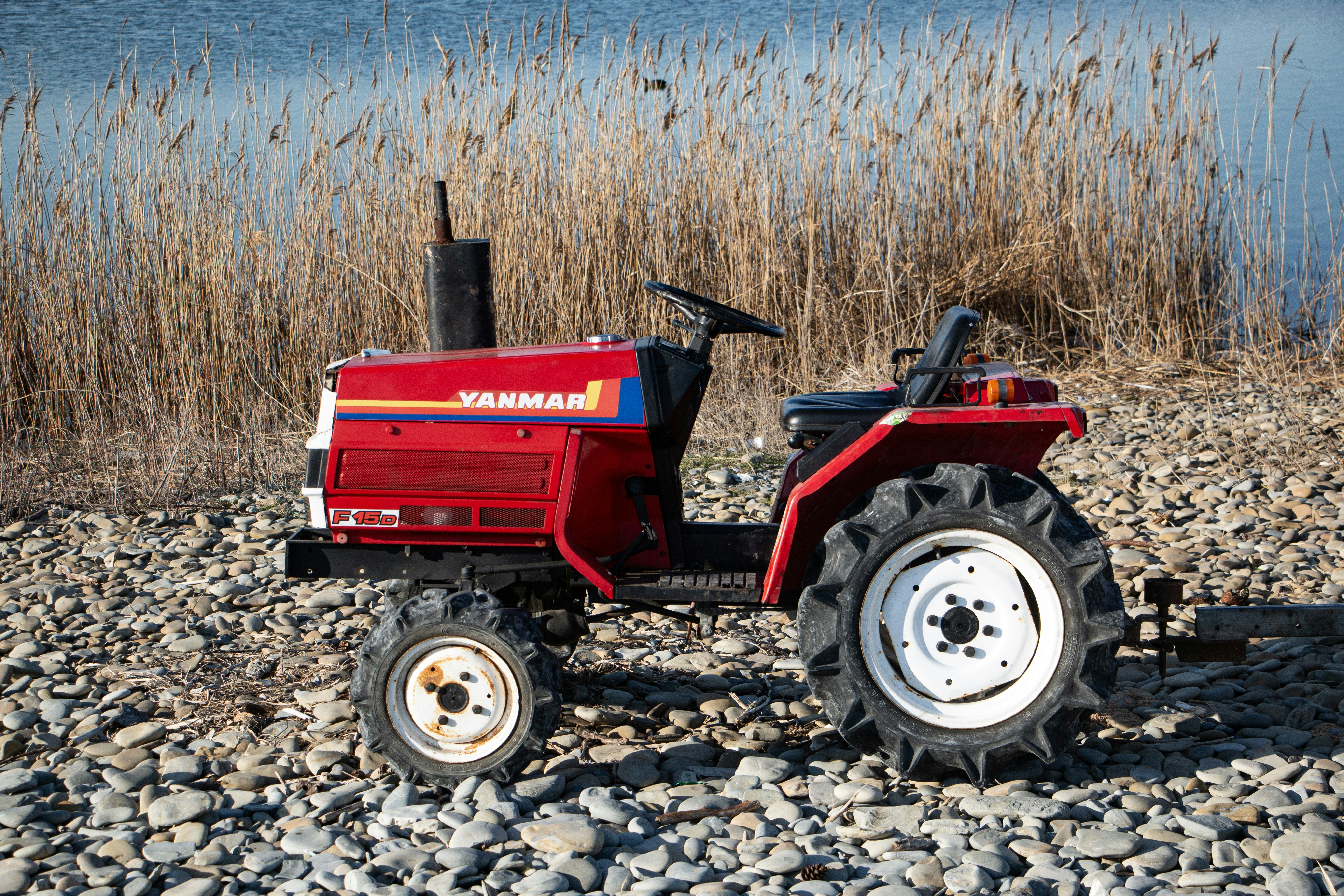 A red tractor sitting on top of a gravel field photo – Free Tracktor ...