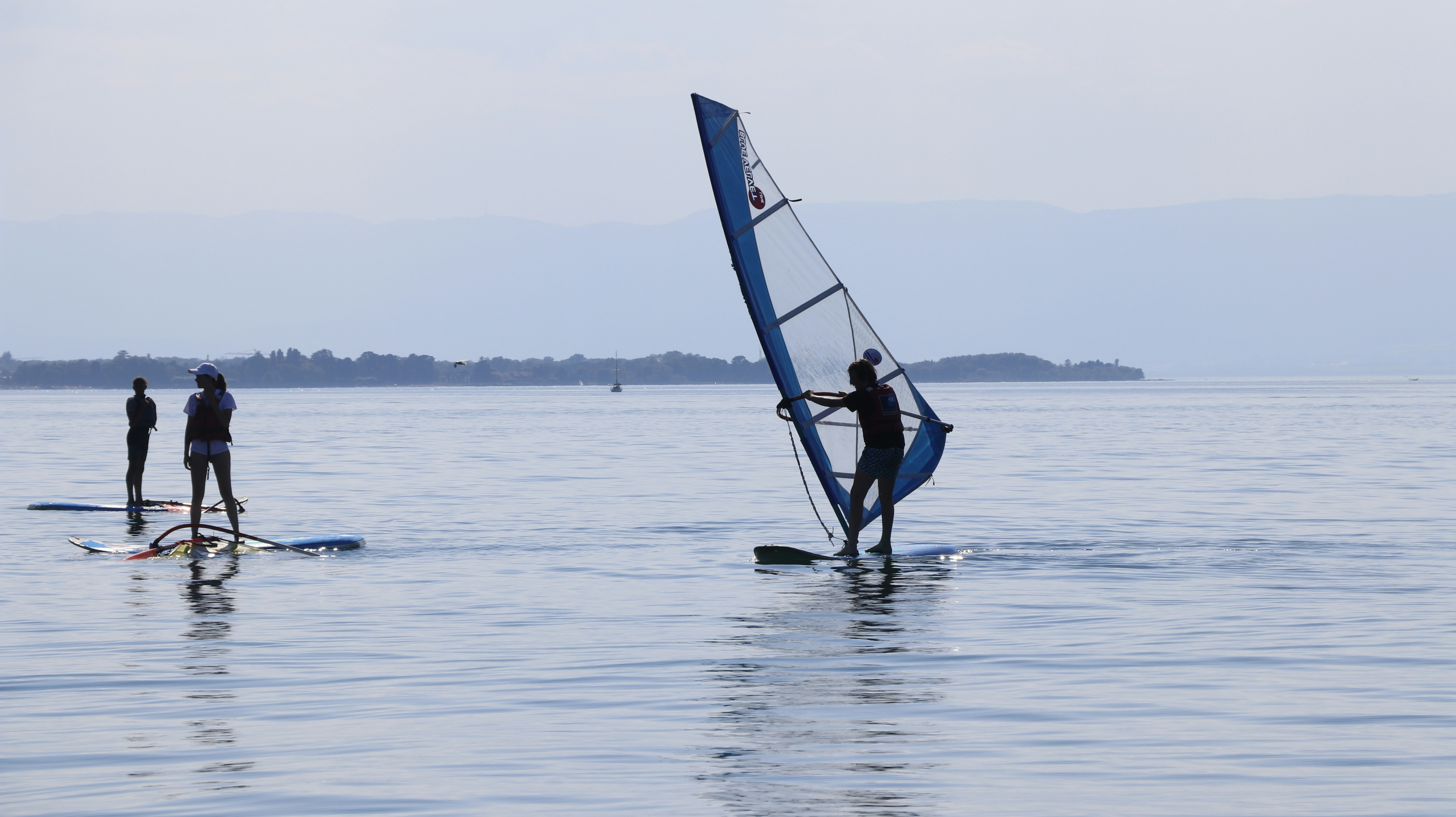 Rightward Glide on a Glassy Bay: Windsurfer in Focus