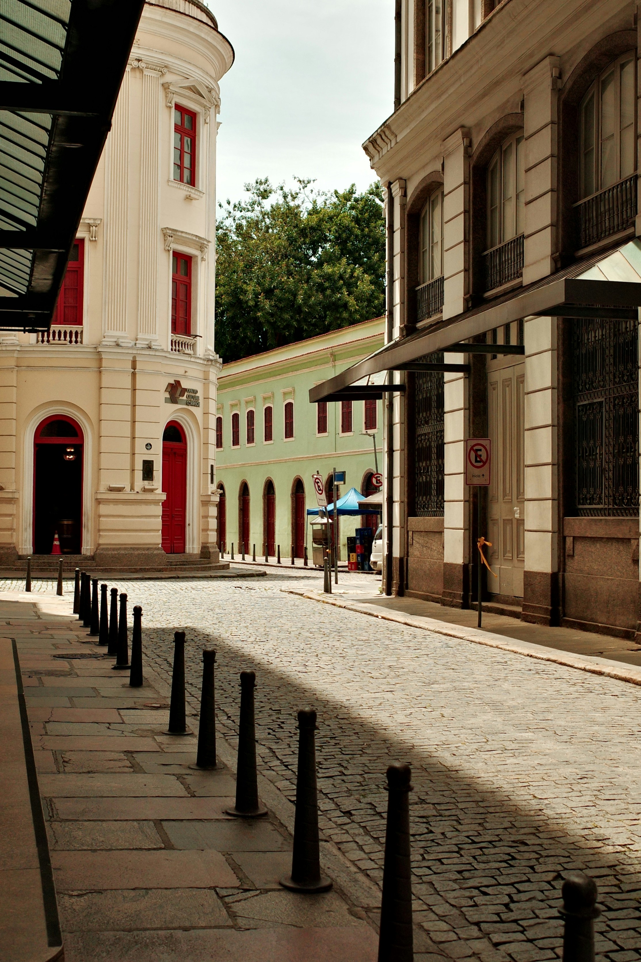 Sunlit Arcades Toward a Pastel Green Facade
