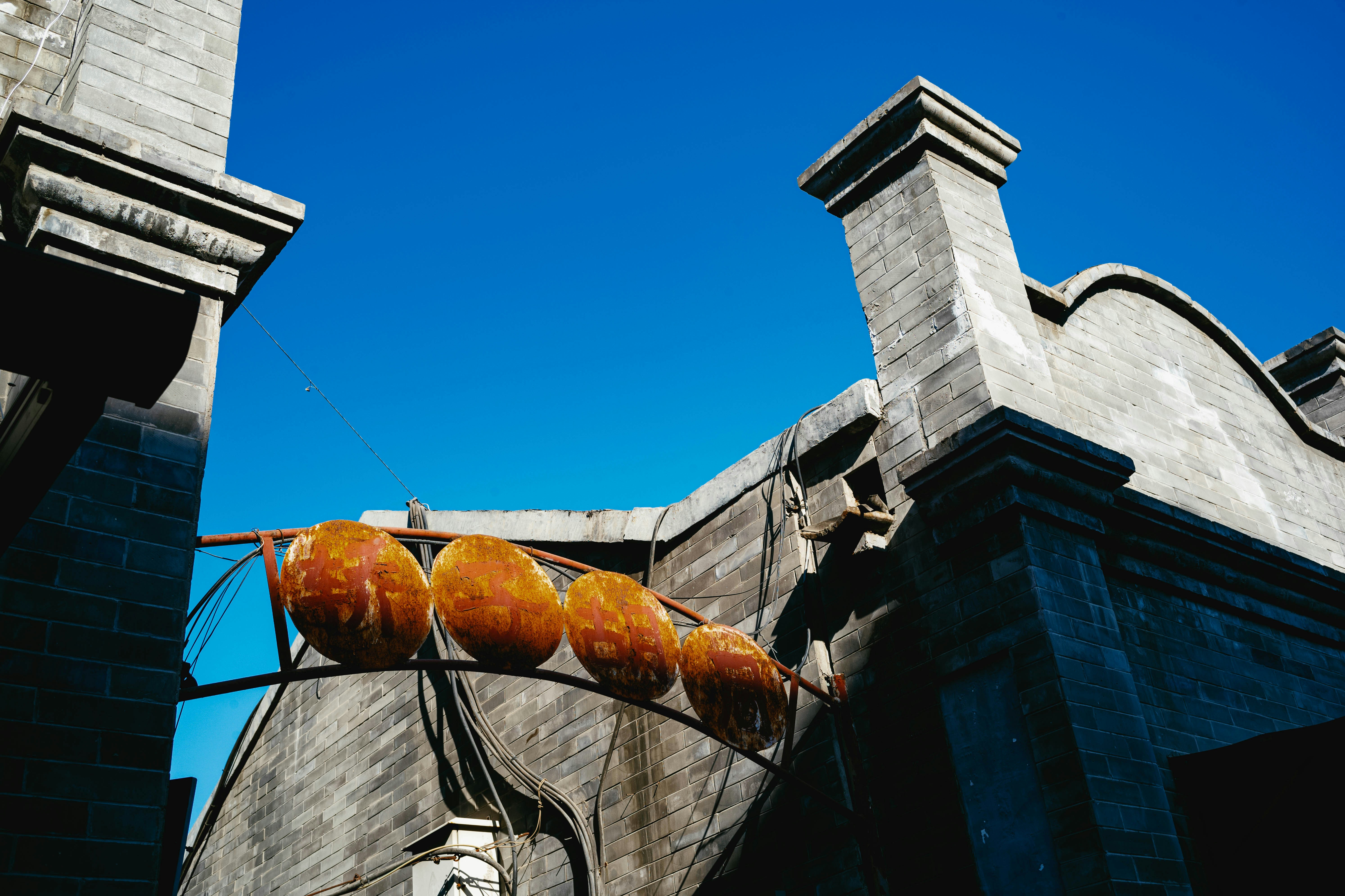 Rust-Orange Orbs Span a Stone Facade Beneath a Bright Blue Sky