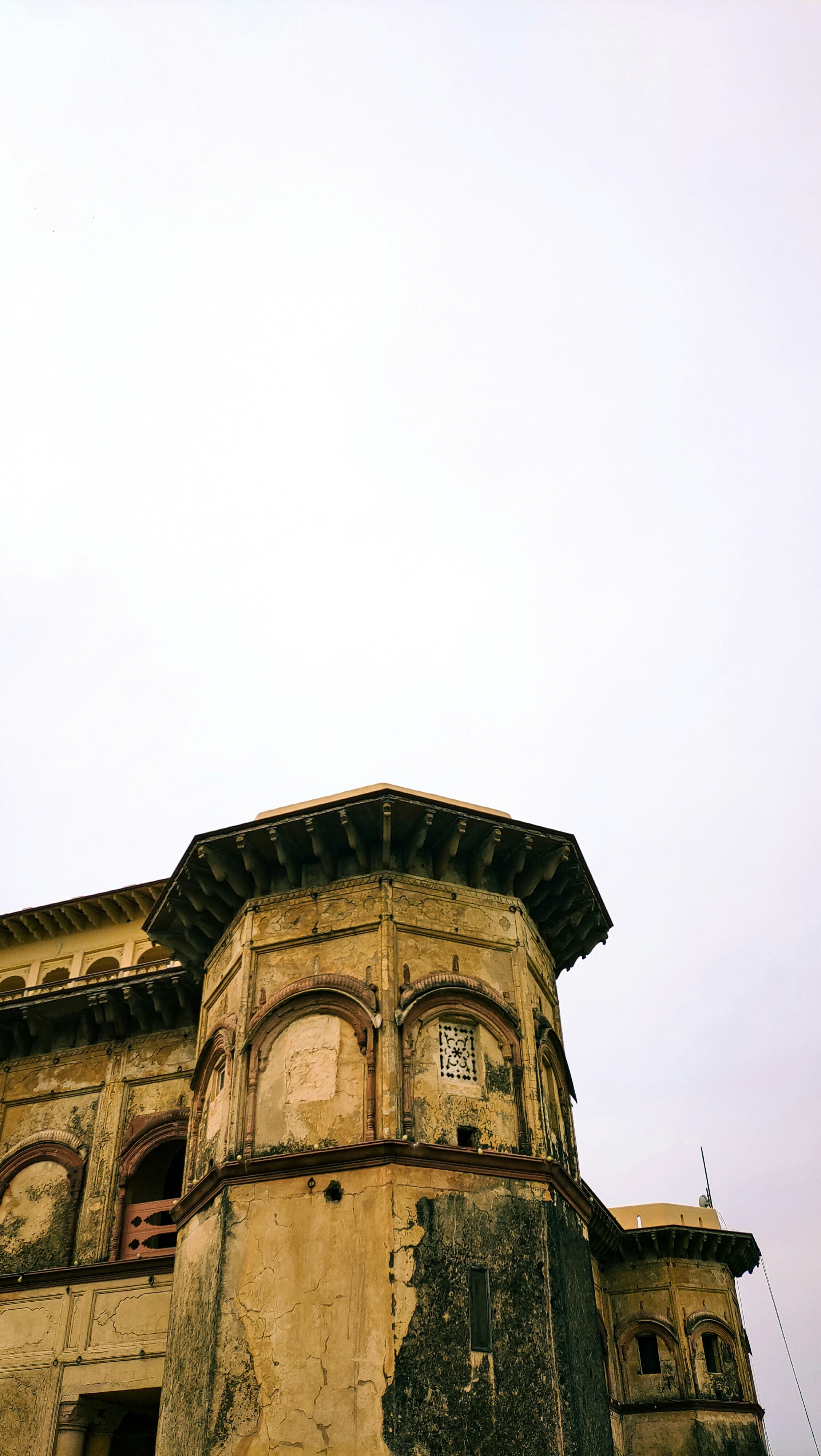 Weathered ancient building with intricate details against a bright sky.