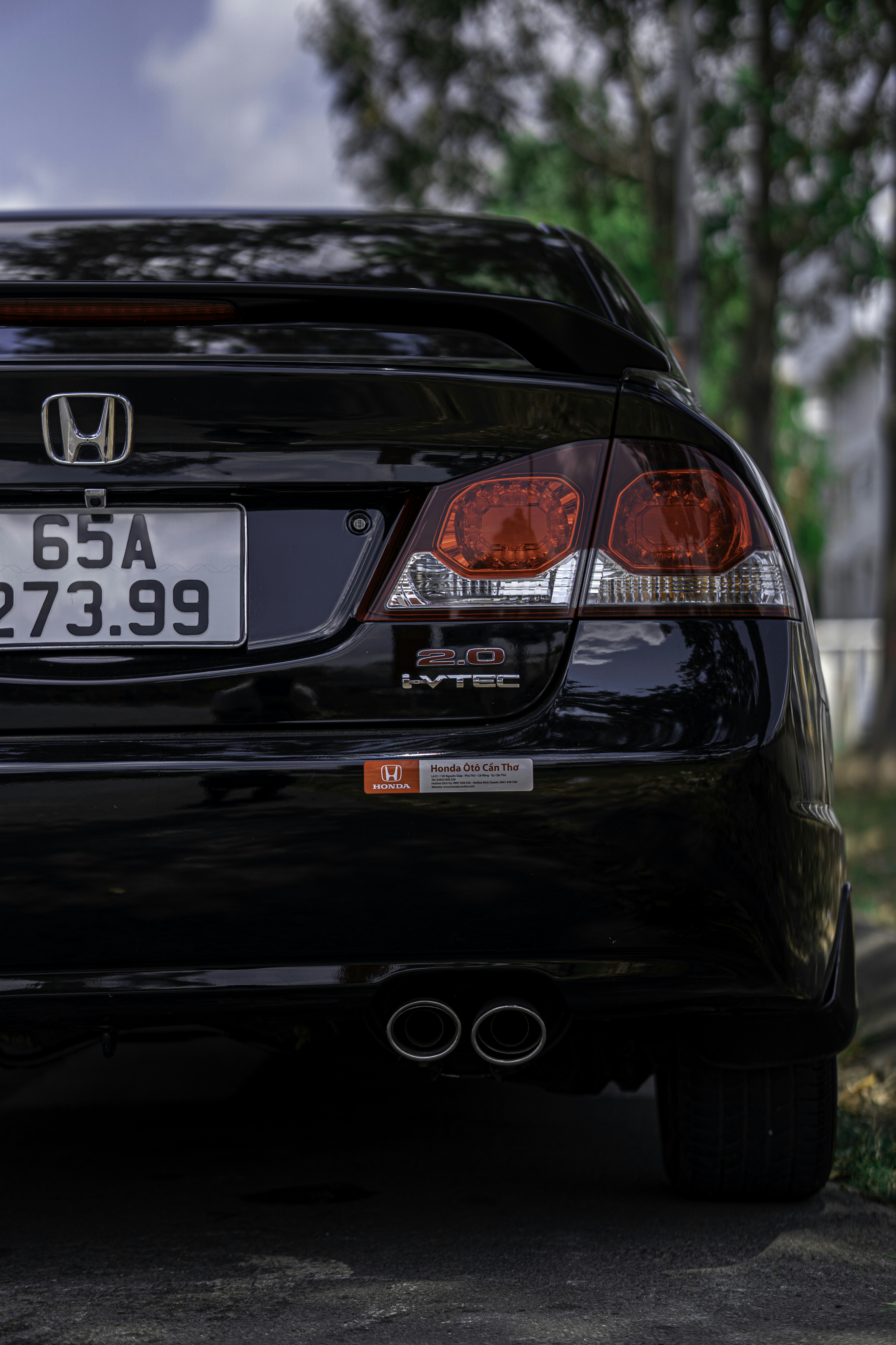 Rear View of a Shiny Black Honda: Tail Lights and Exhaust in Focus