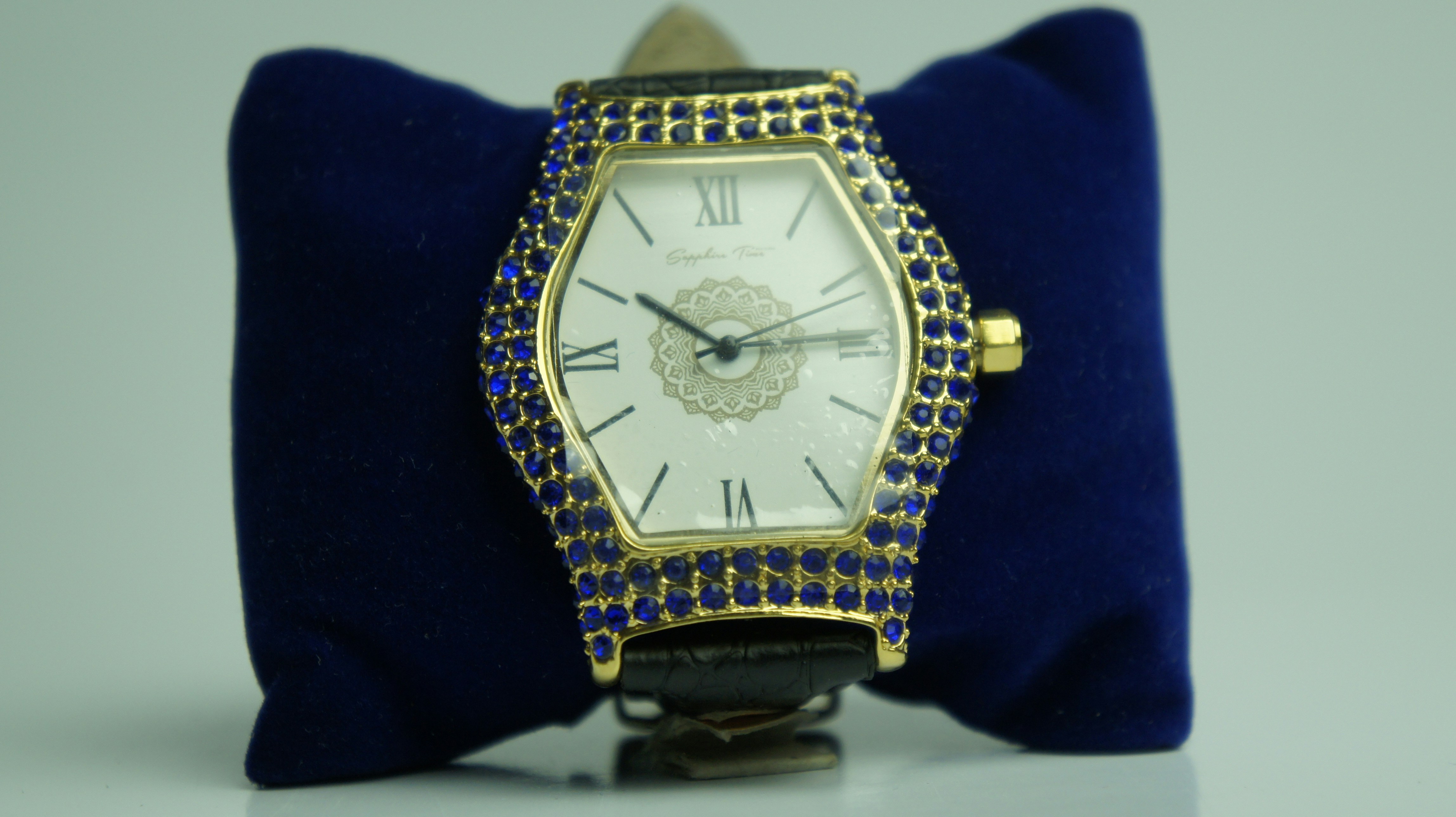 Blue Crown of Time: Jewel-Encrusted Gold Watch on Velvet
