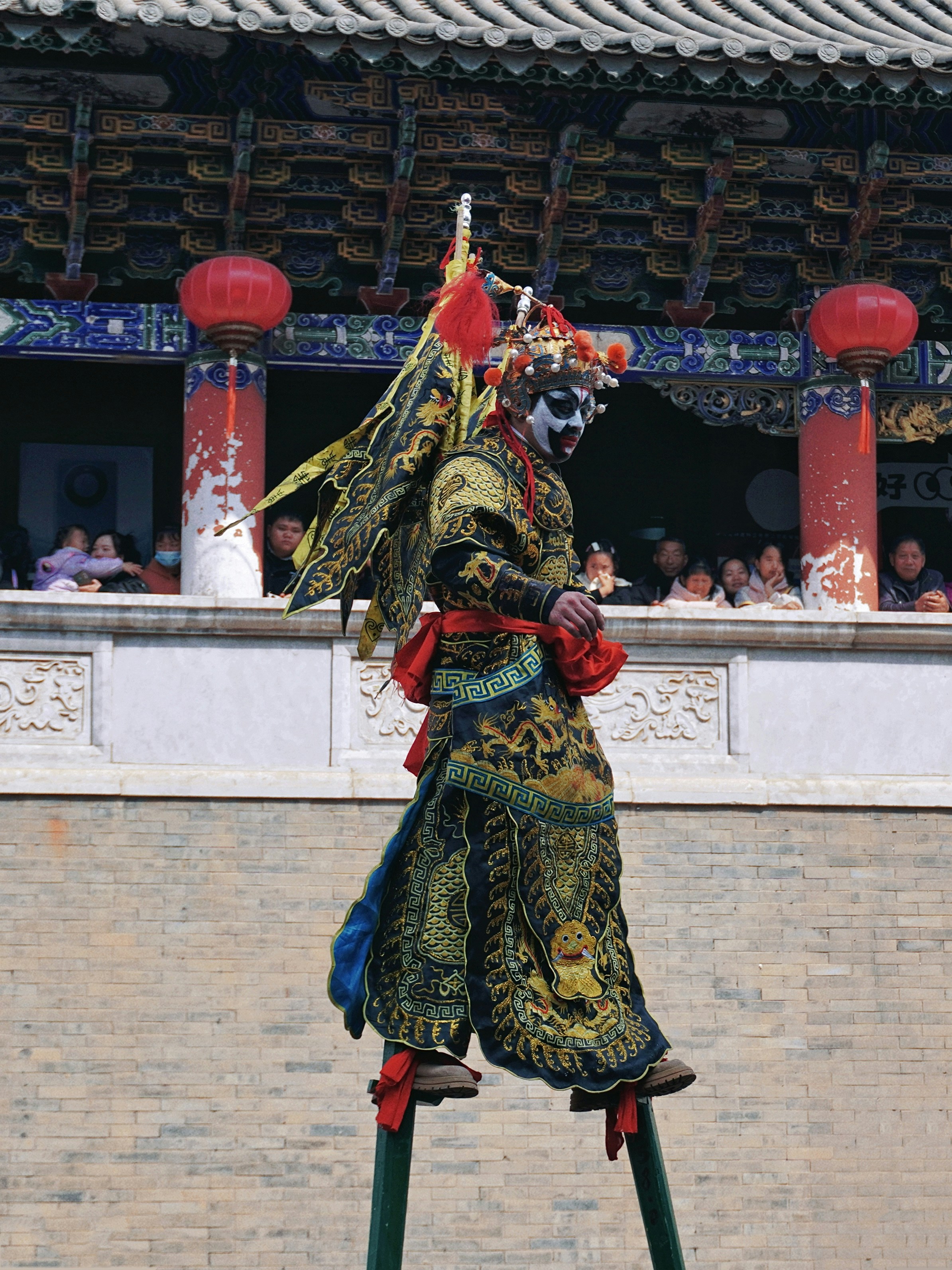 A person in a costume standing on stils in front of a building photo ...