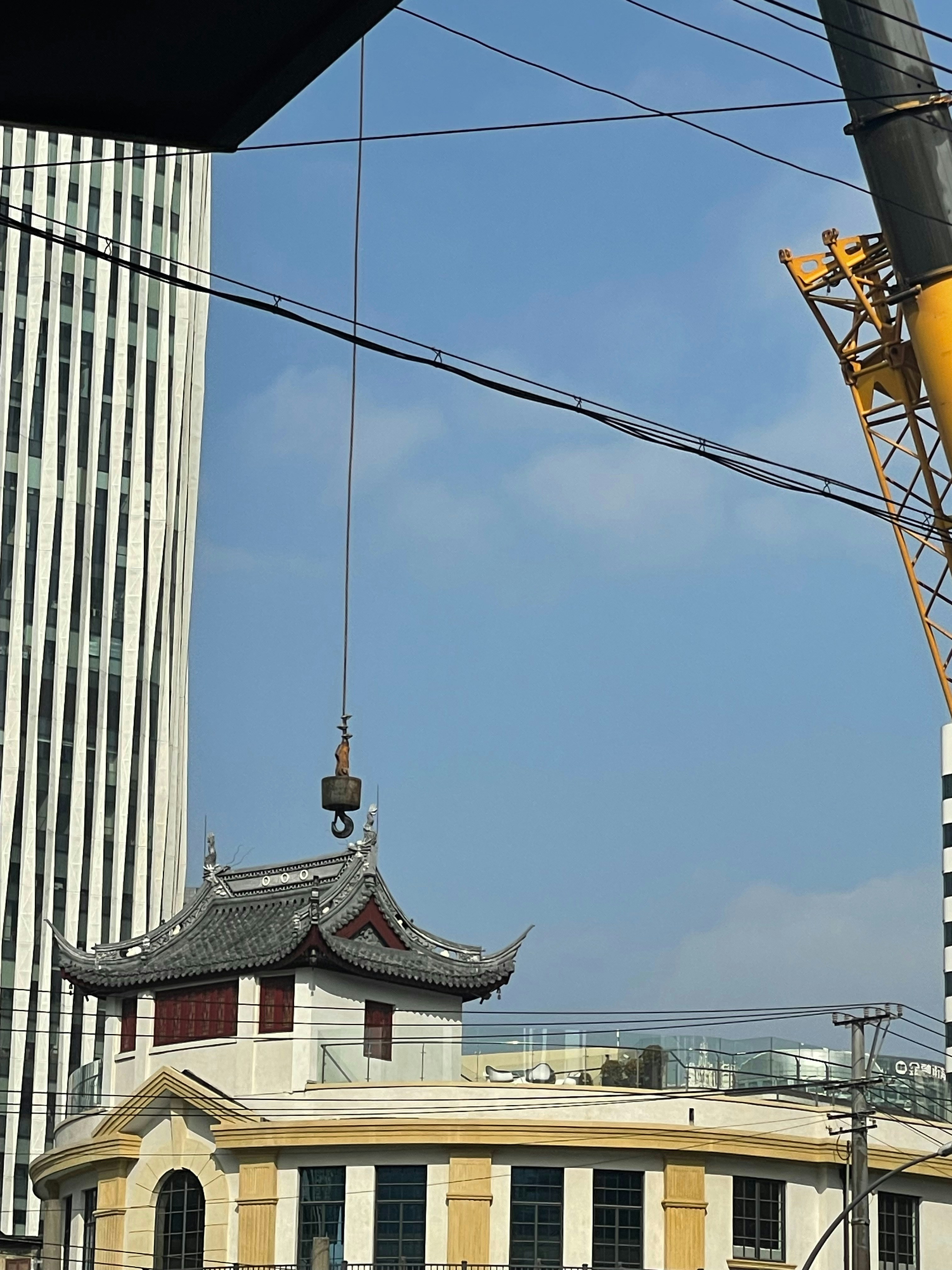 Roofline Reverie: Traditional Pavilion Framed by Modern Skyscraper and Crane