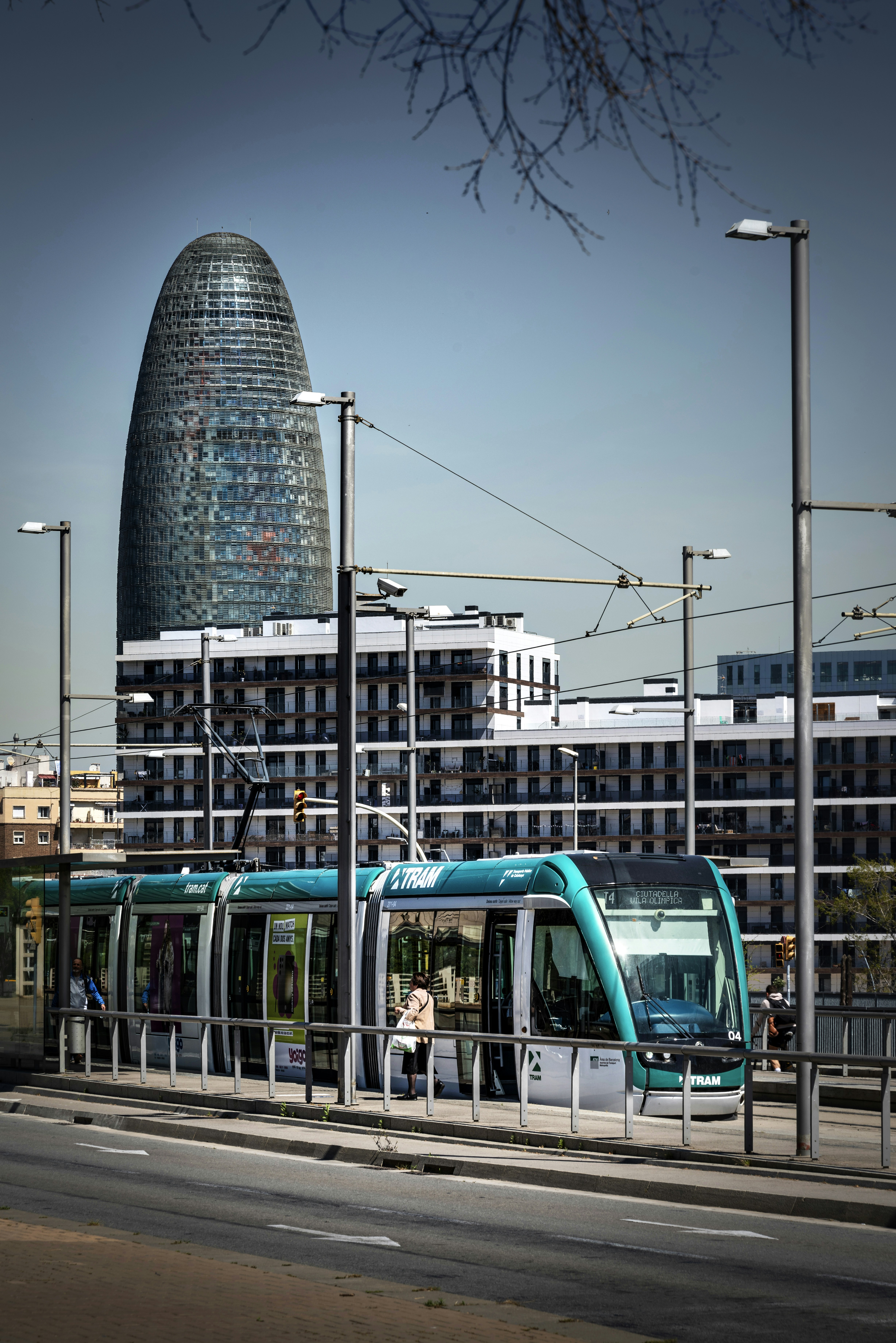 Teal Tram Under the Blue Glass Tower: A Barcelona Street Moment