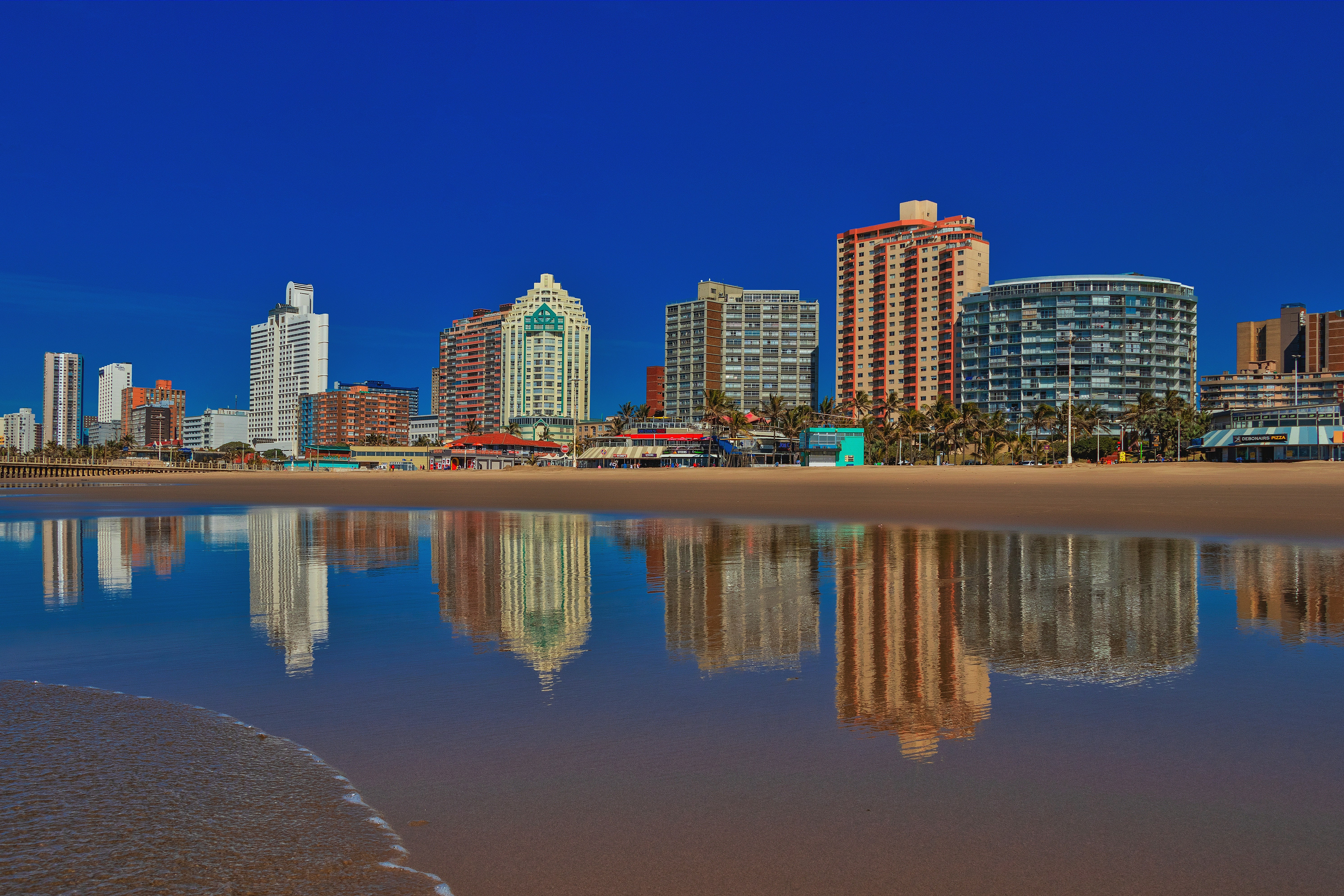 A view of a beach with a city in the background photo – Free Water ...