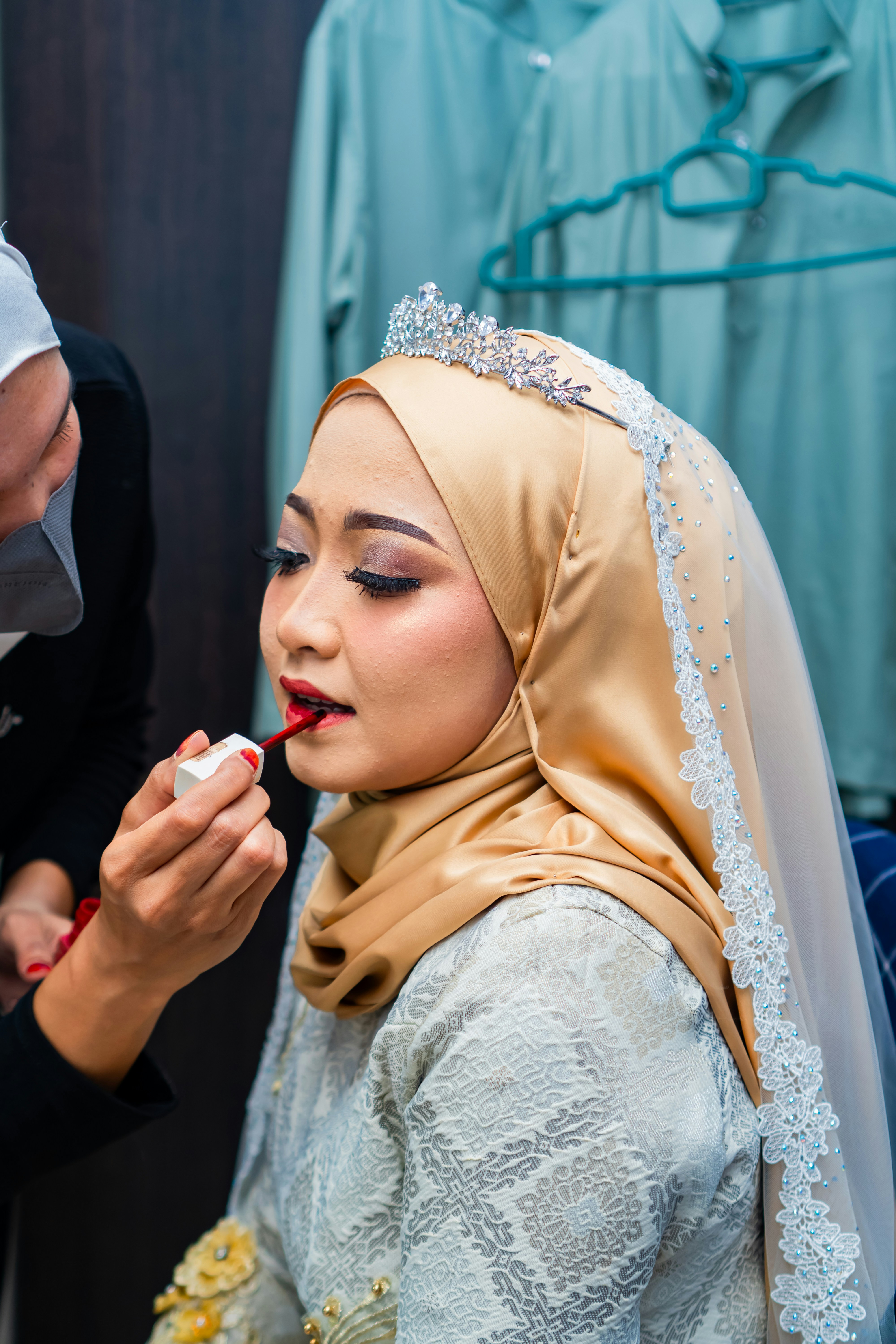 A woman in a hijab putting lipstick on her lips photo – Free Cosmetics ...