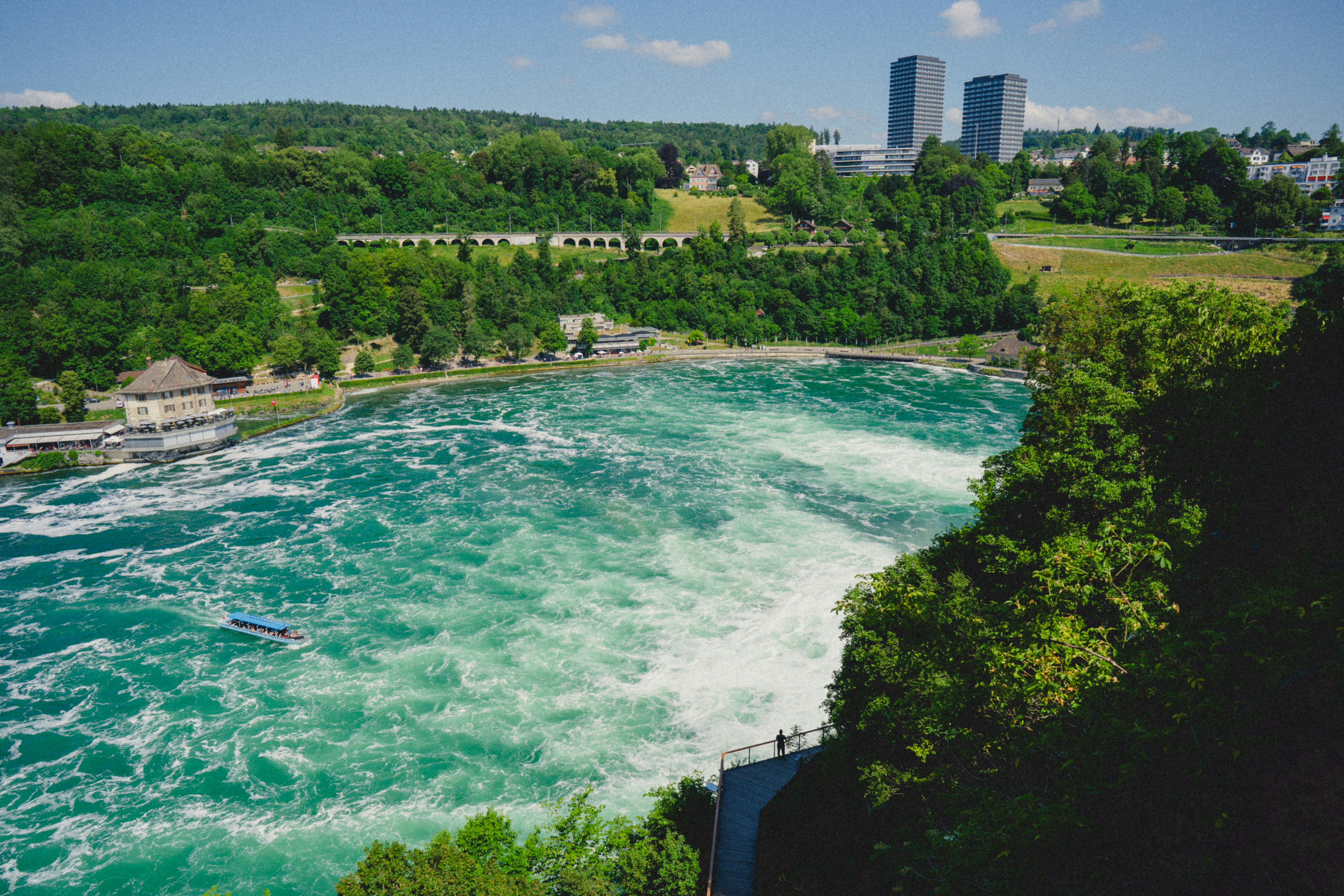Turquoise Rapids Overlook: Riverbank Greens Meet a Distant Skyline